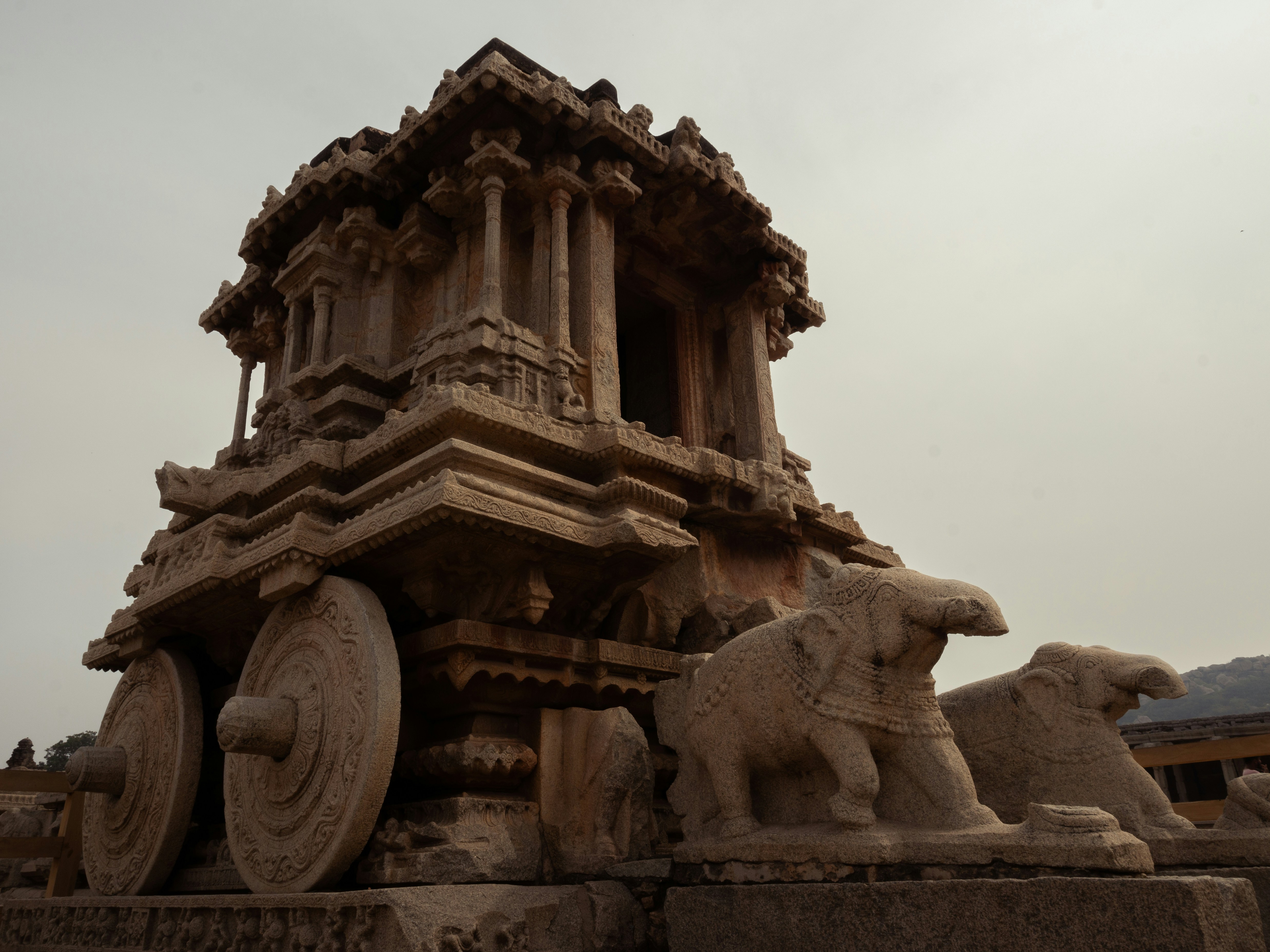 Weathered Temple Chariot: Guardians in Stone Under Gray Skies