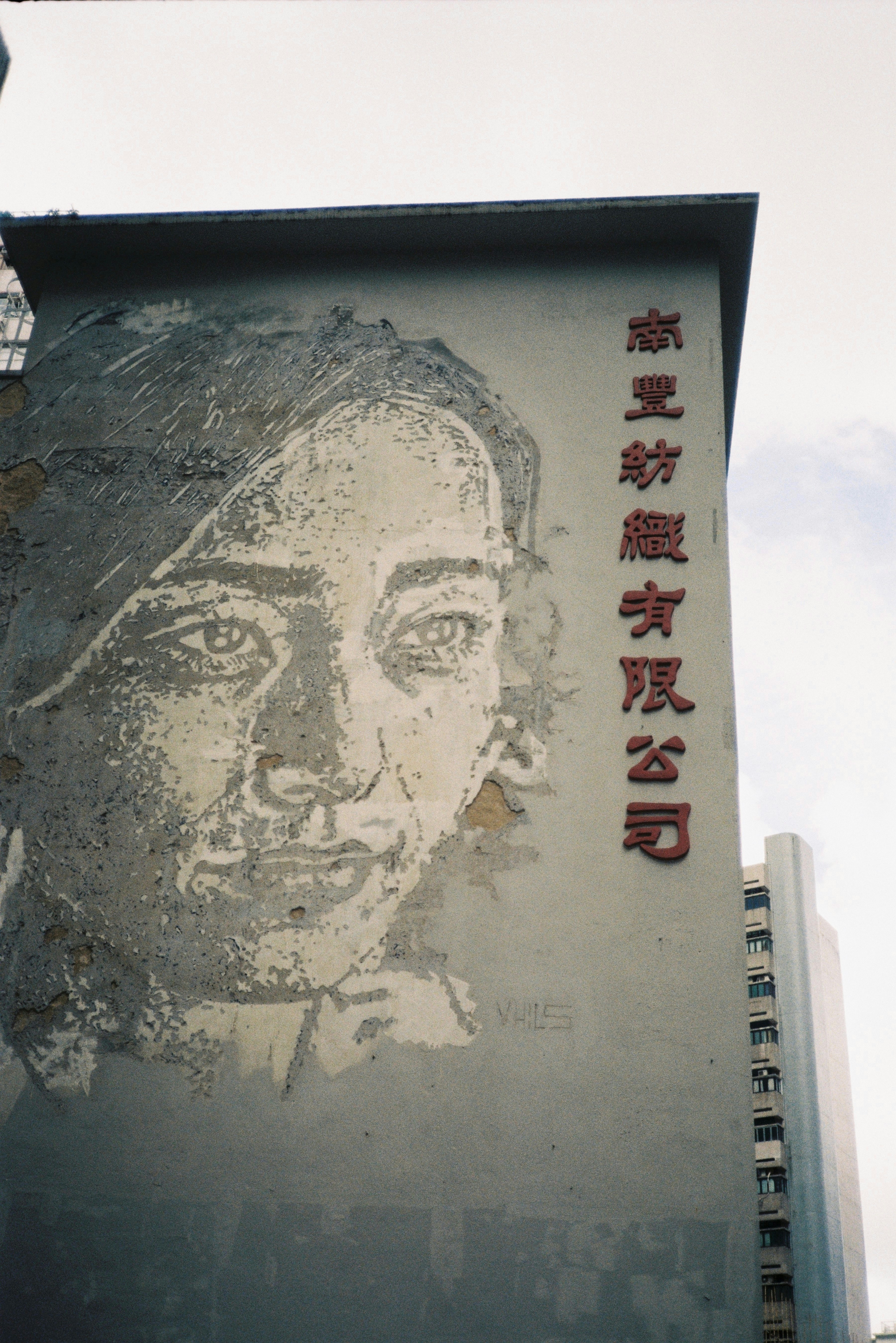 Portrait of a City Wall: Red Characters Beside a Weathered Face