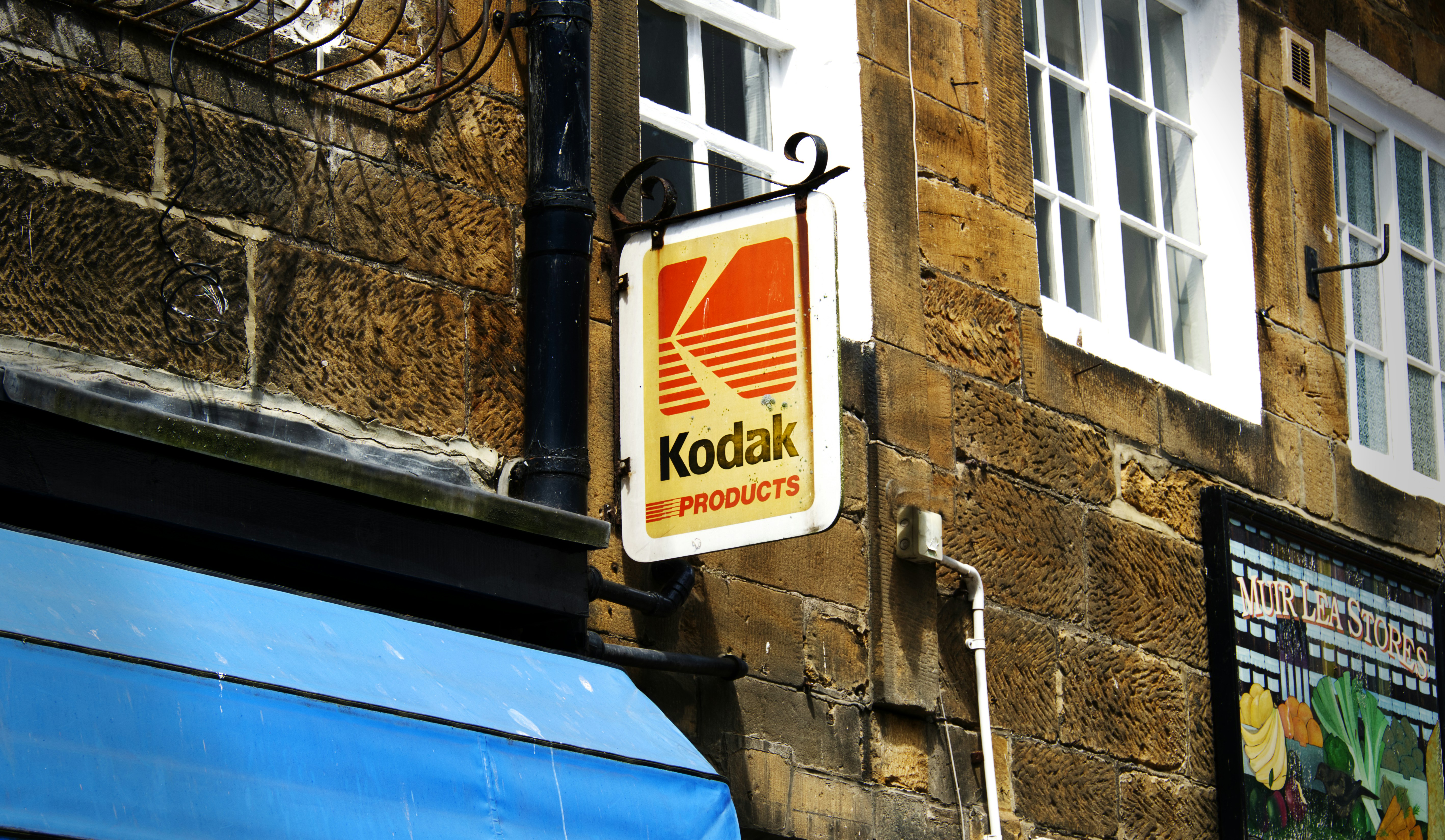 A store front with a sign hanging from the side of it photo – Free ...