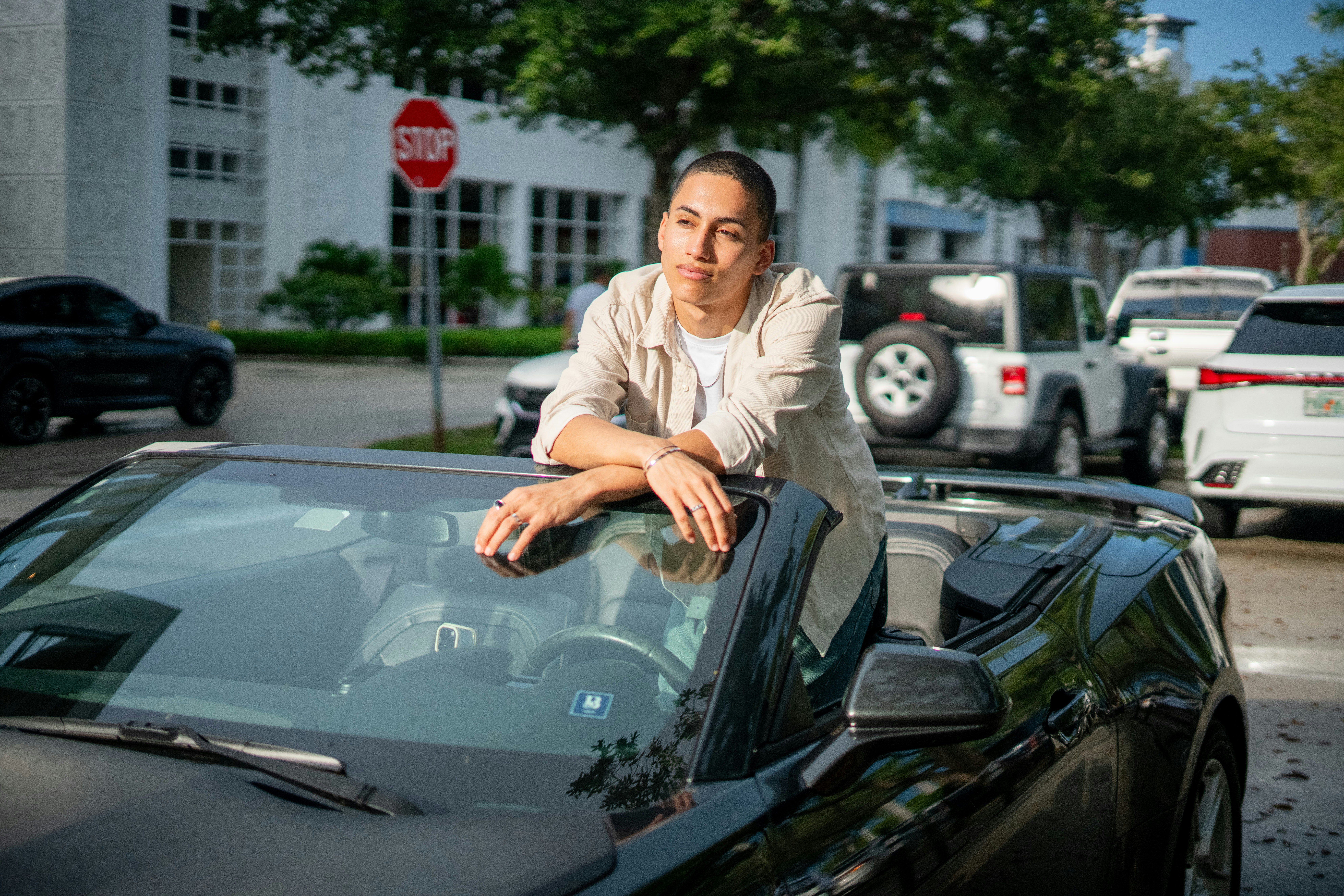 Leaned-in Moment: a jogger-like figure atop a convertible in daylight