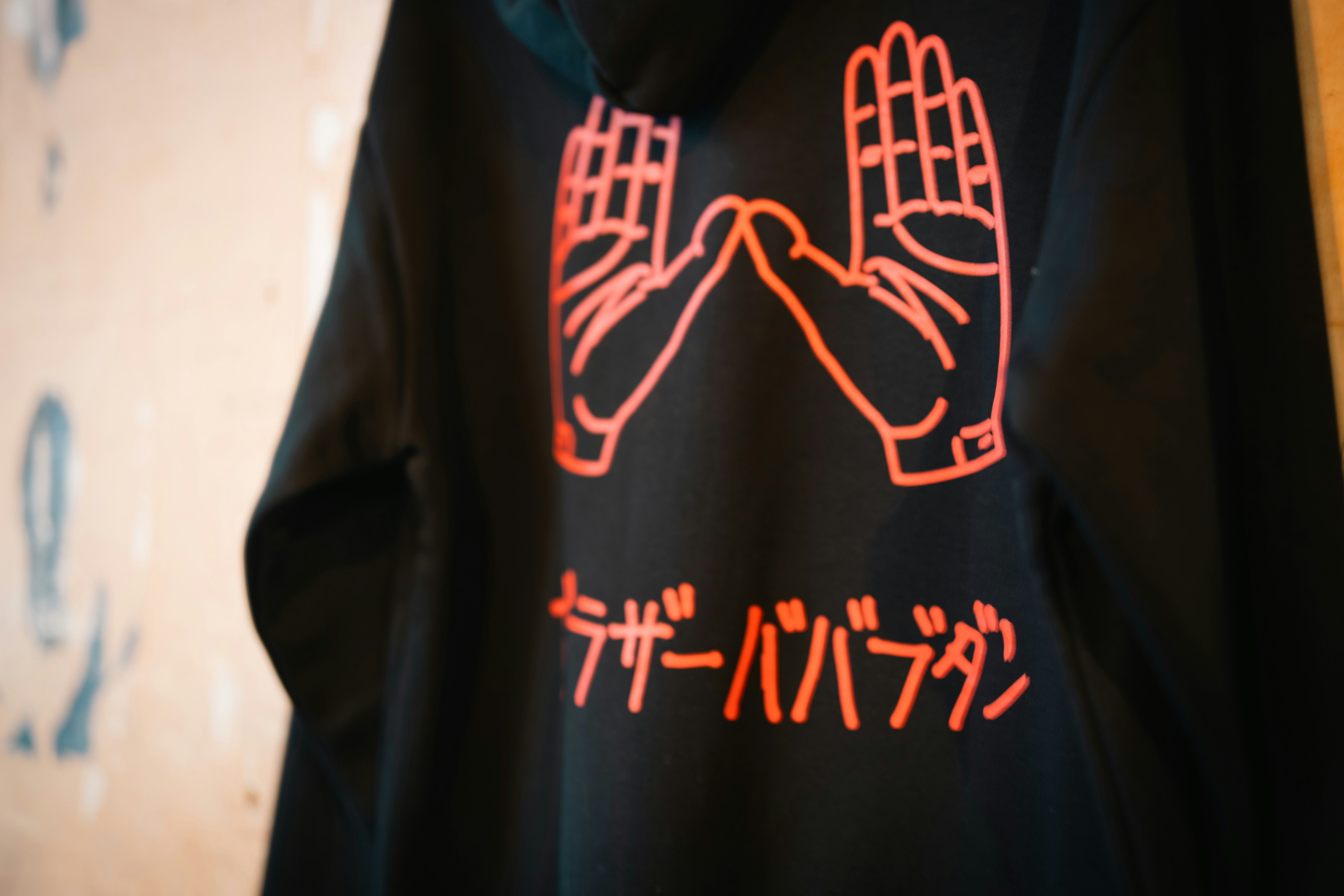 Neon-Outlined Hands Embrace a Black Hoodie with Japanese Script