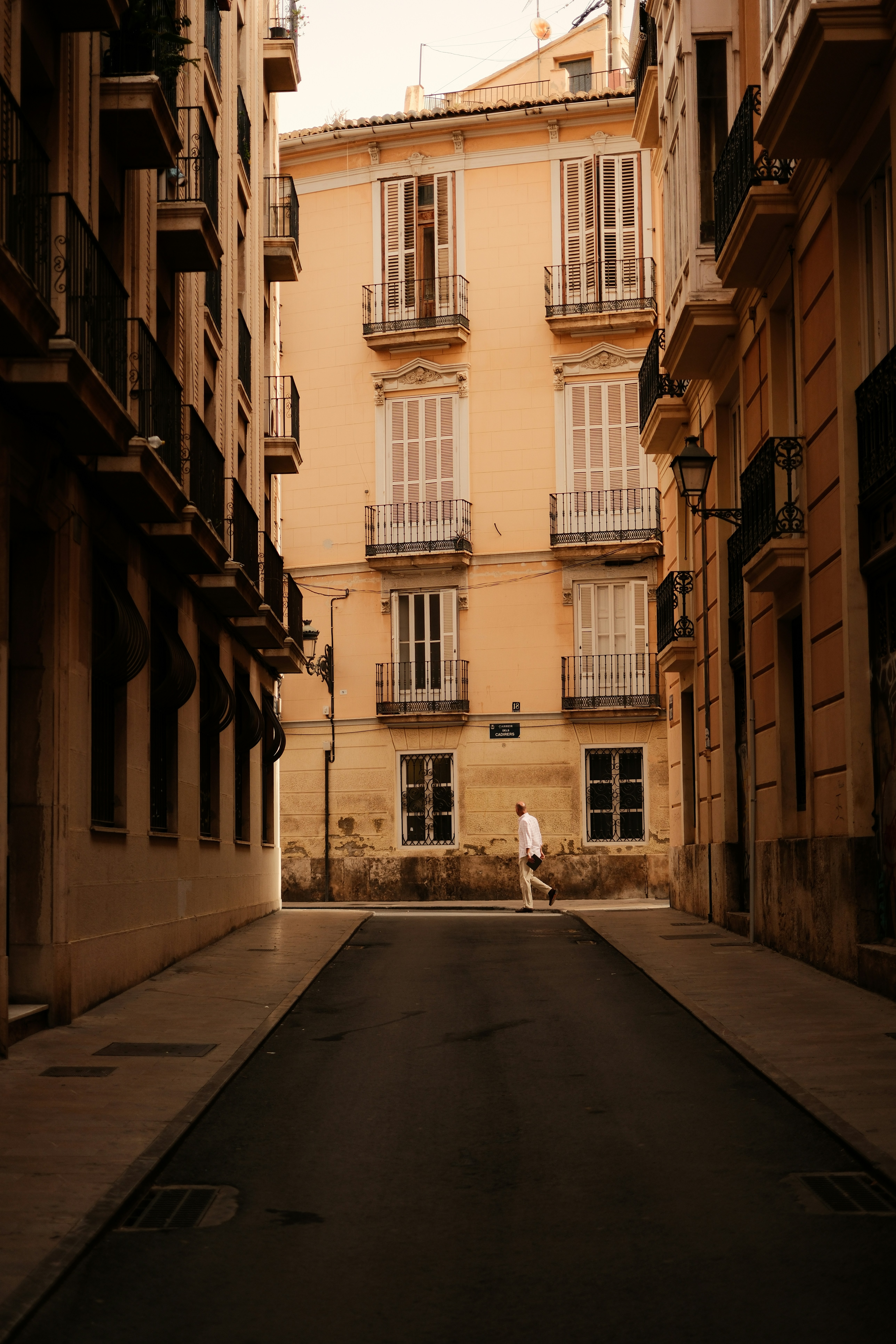 A narrow street with a person walking down it photo – Free Building ...