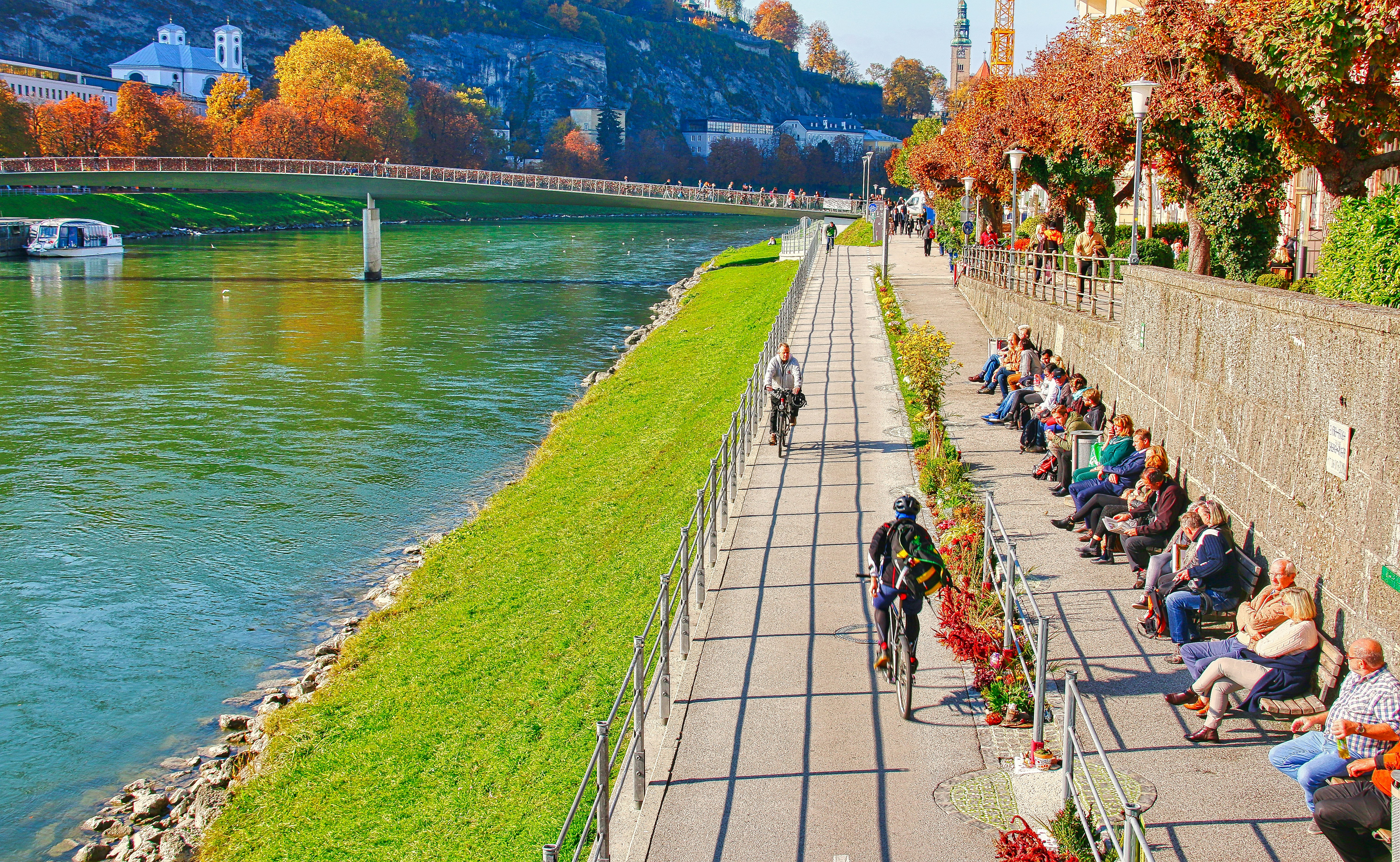 Riverside Parade: Cyclists and Spectators Along the Sunny Bank