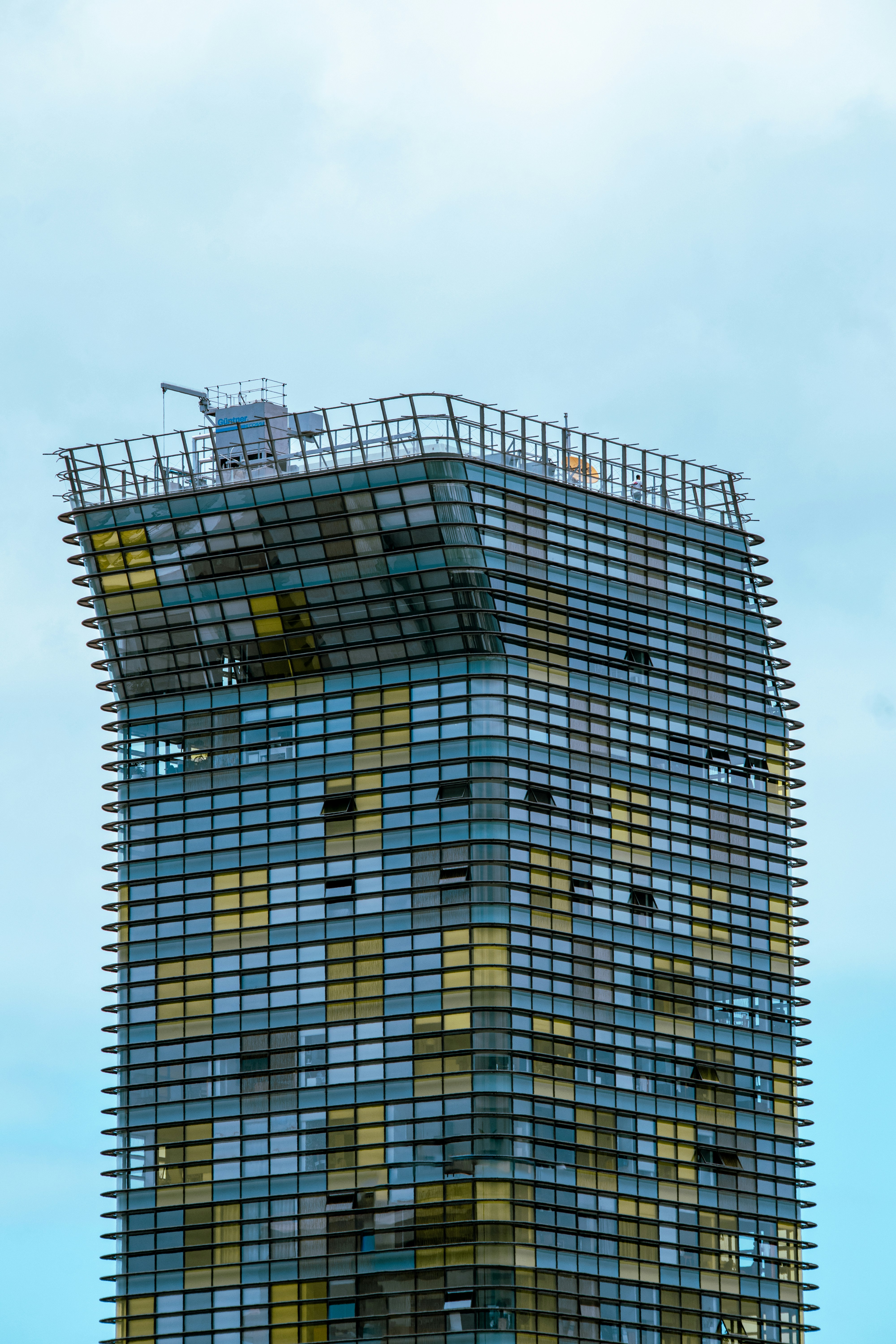 Grid-Wrapped Skyscraper Rising Against a Pale Blue Sky