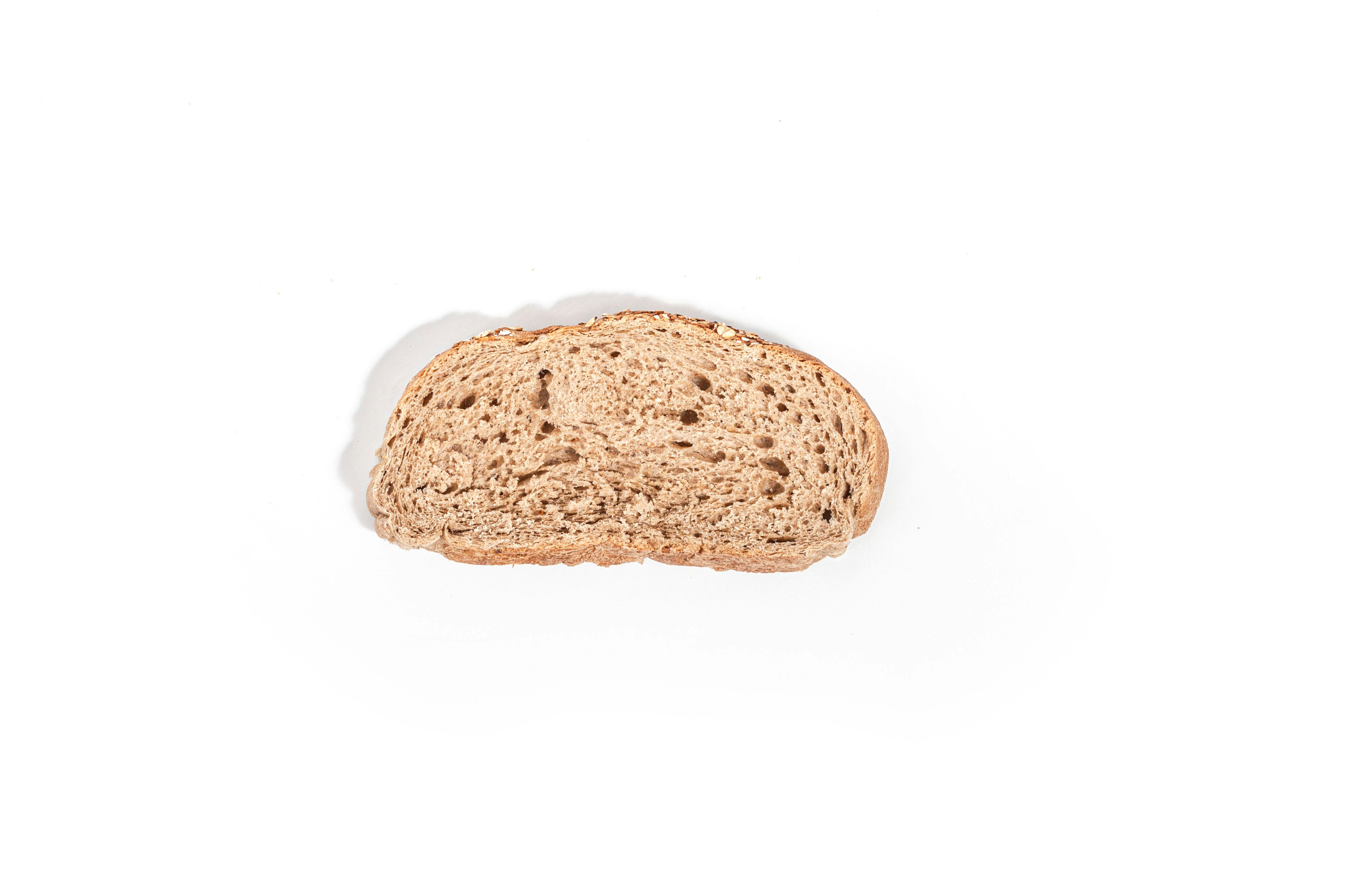 Grain on a Pure White Stage: A Lone Slice of Brown Bread