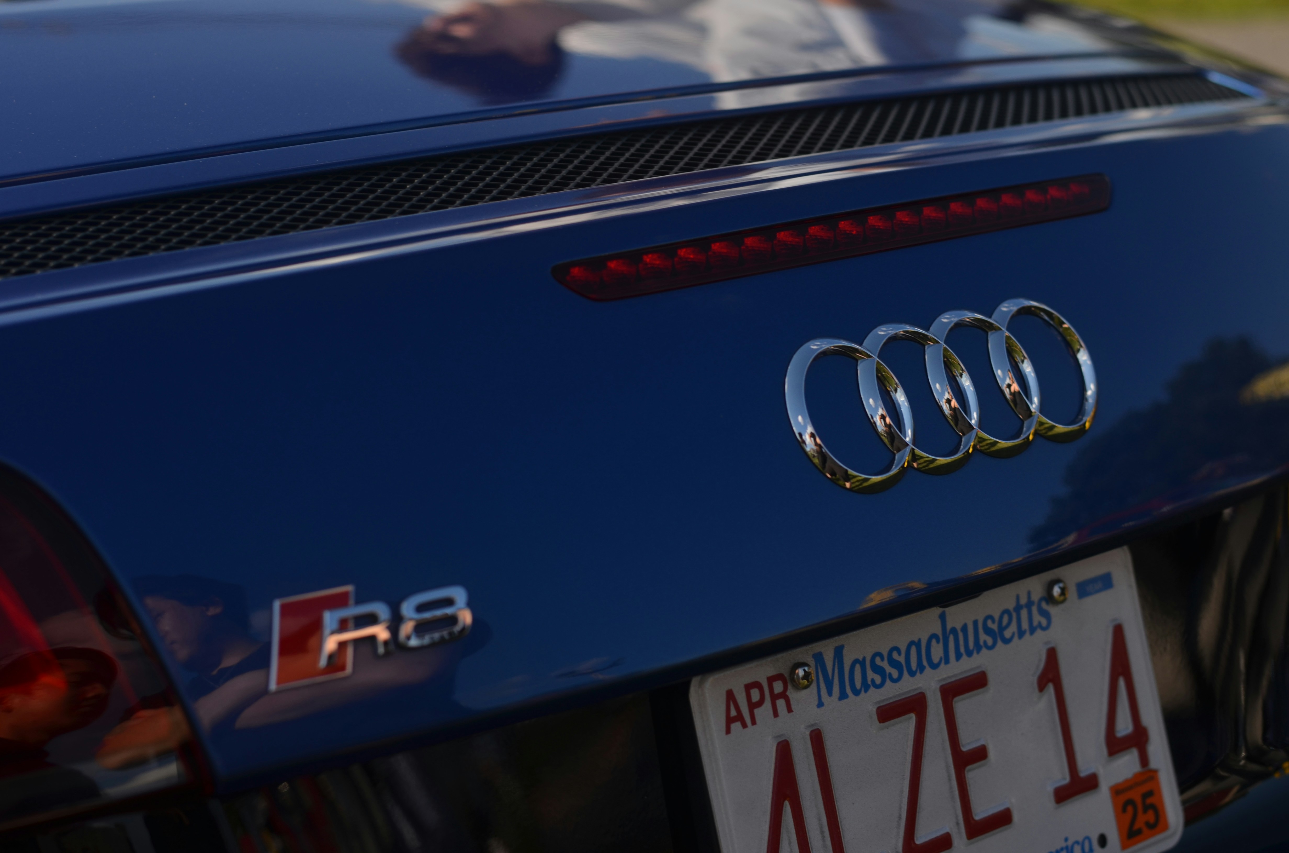 Blue Chrome and Badge Focus: Close-Up of Audi R8's Rings beside a Massachusetts Plate
