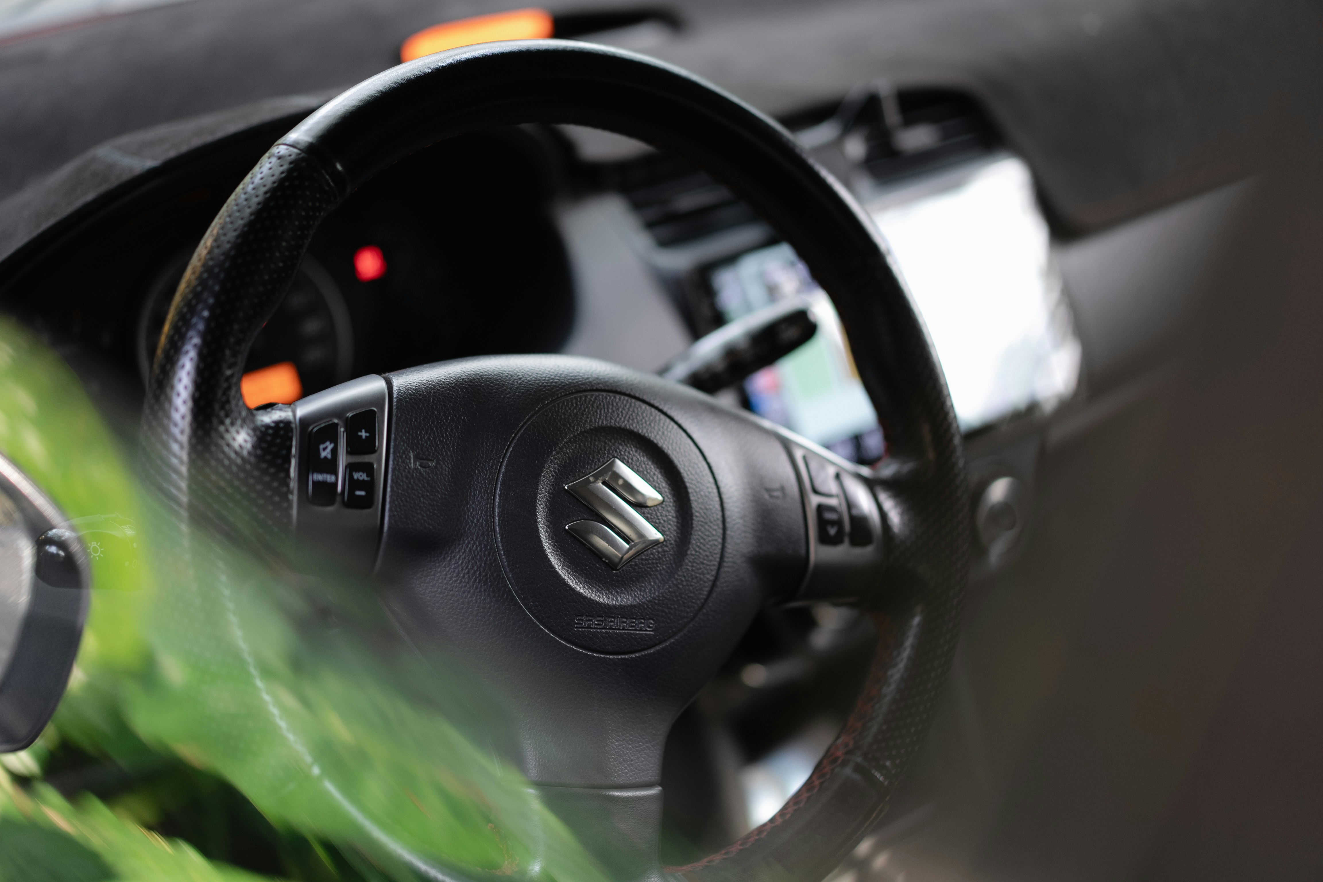 Steering wheel of Suzuki Swift. | A close up of a steering wheel and dashboard of a car