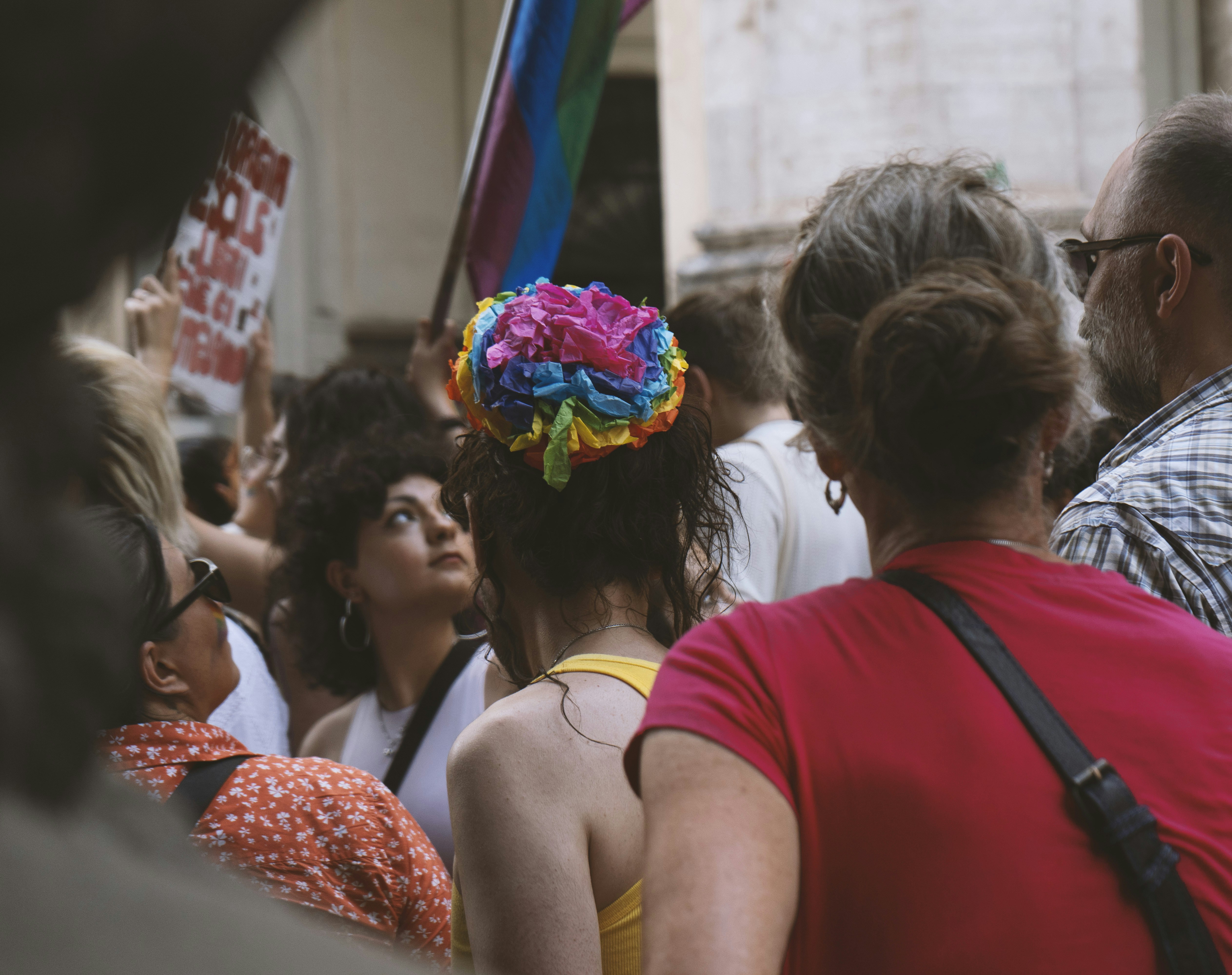 Participants at a lively event display a rainbow-themed accessory, symbolizing pride and inclusivity. The scene captures a moment of togetherness amidst a diverse gathering.