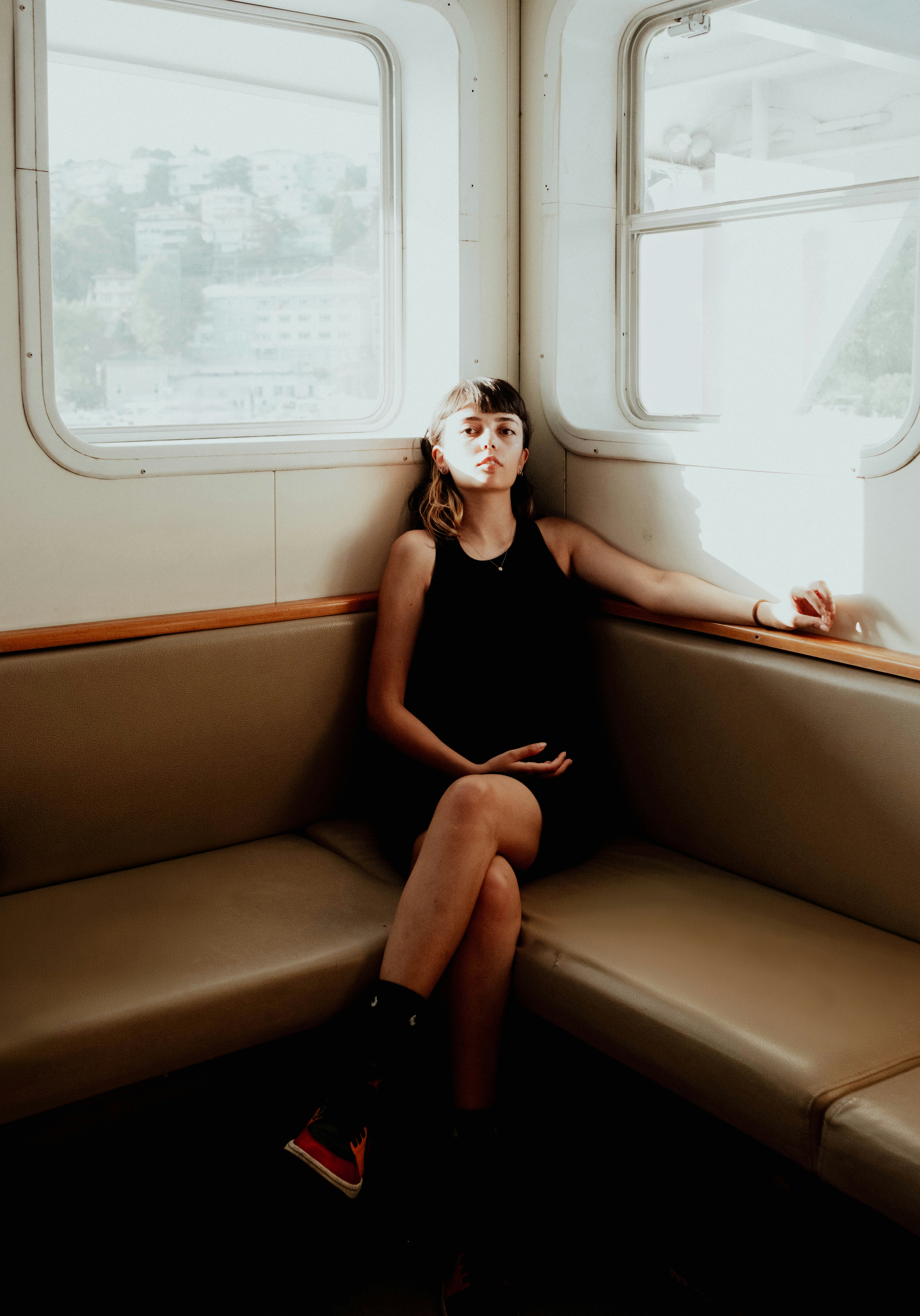 A woman sitting on a bench in front of a window photo – Free Model ...
