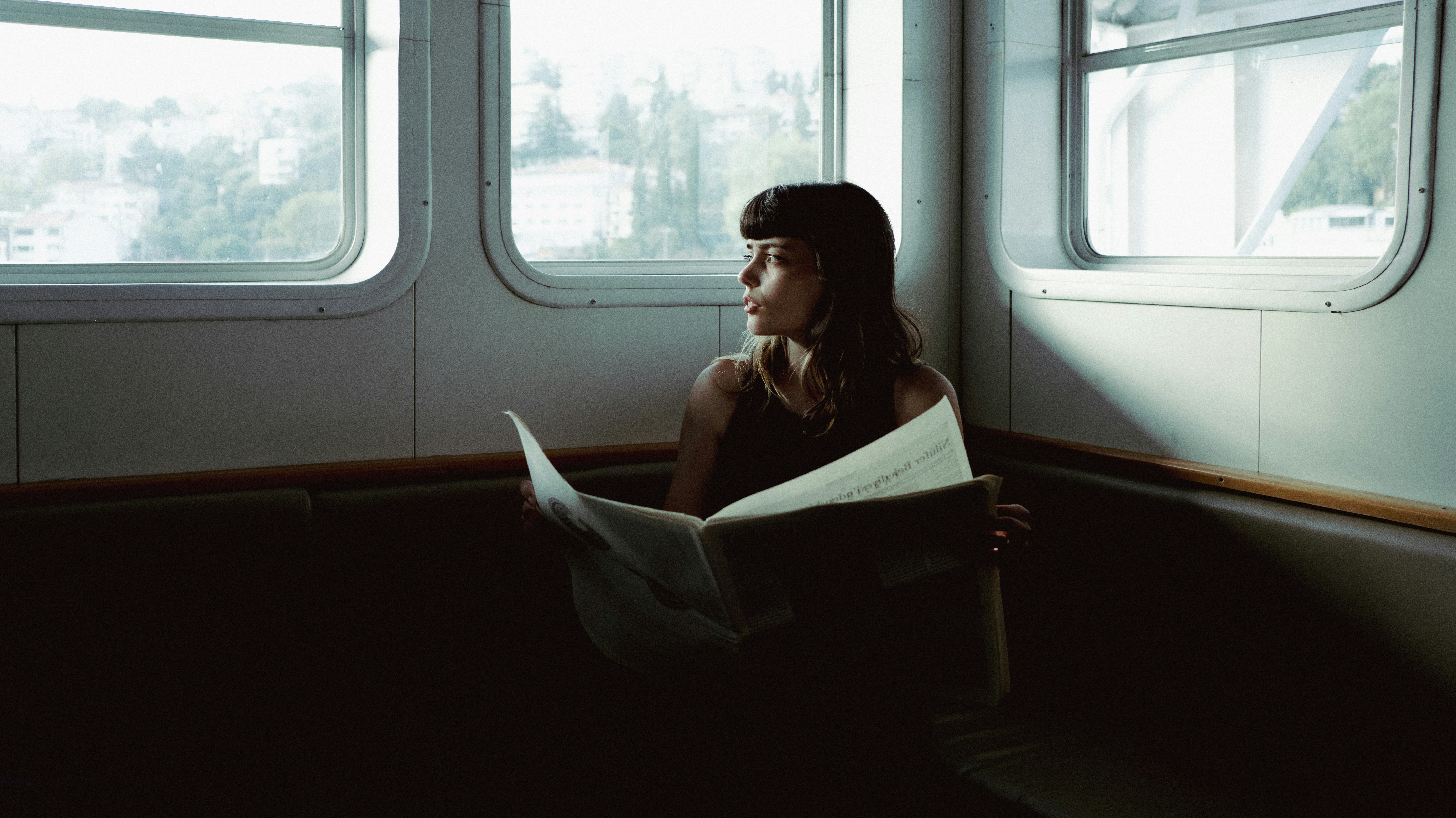 Quiet Spotlight: A Reader in Half-Light on a Harbor Train