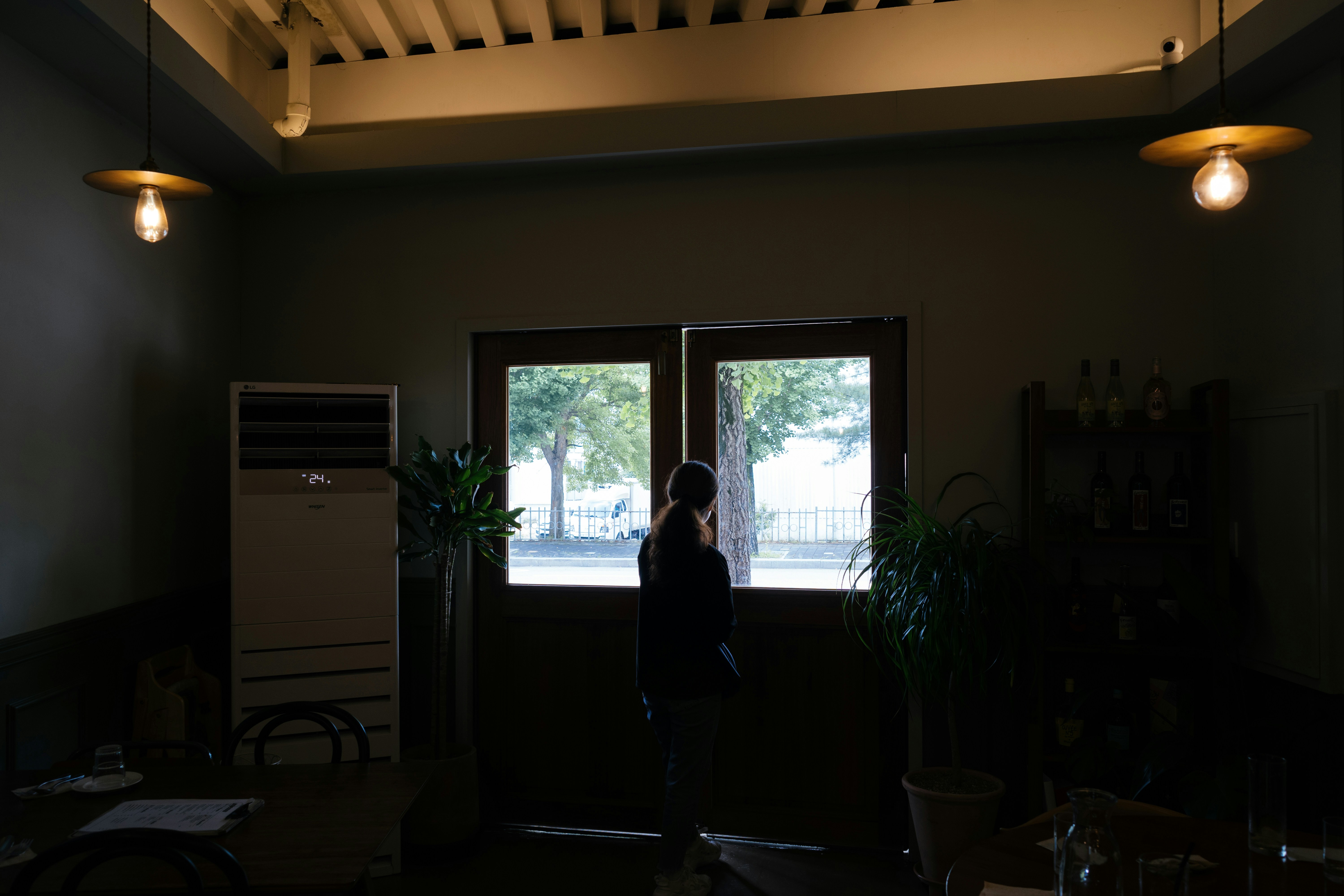 A person standing in a dark room looking out a window photo – Free ...