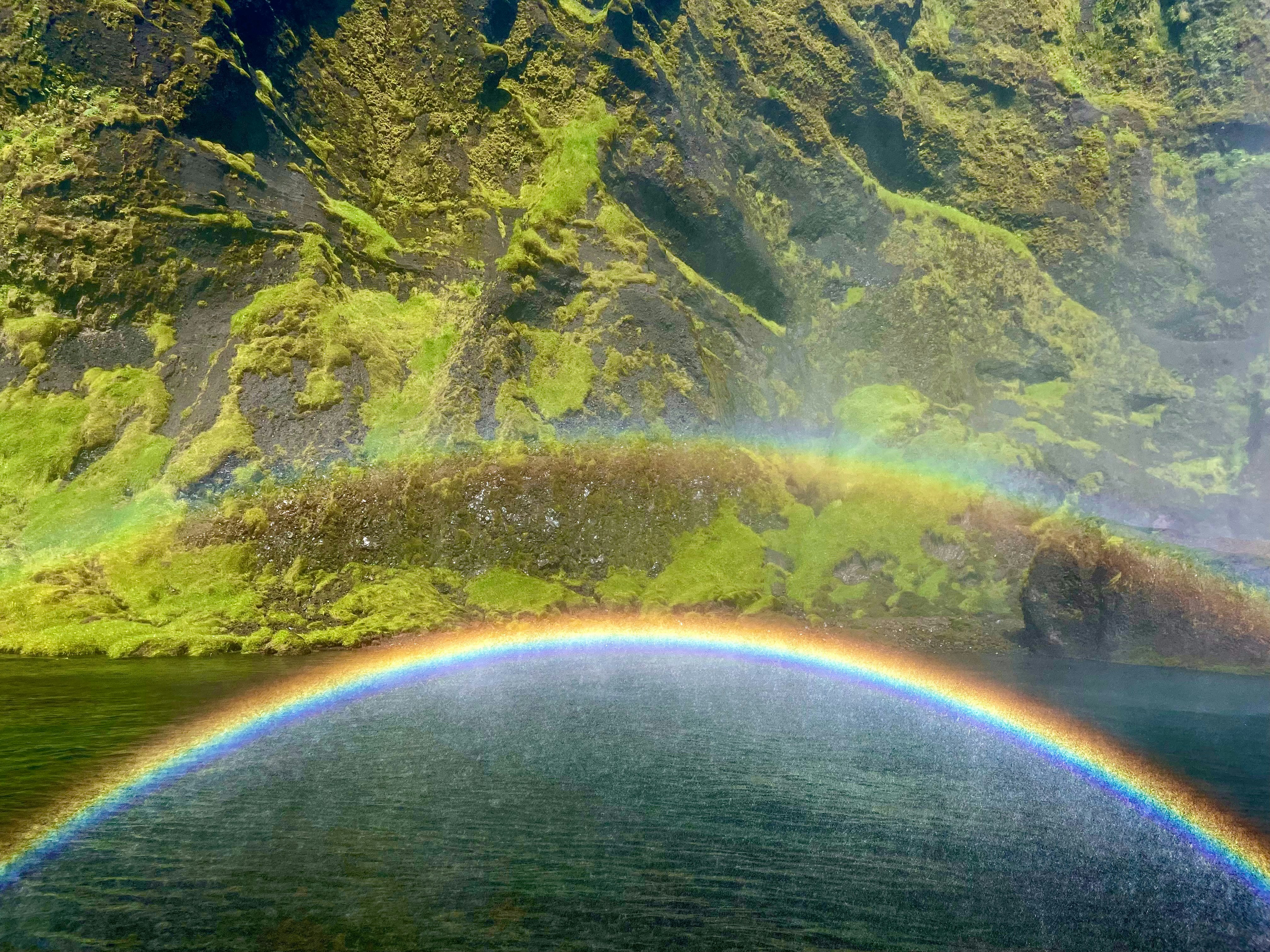 Twin Rainbows Over Emerald Pool Beneath Mossy Cliffs