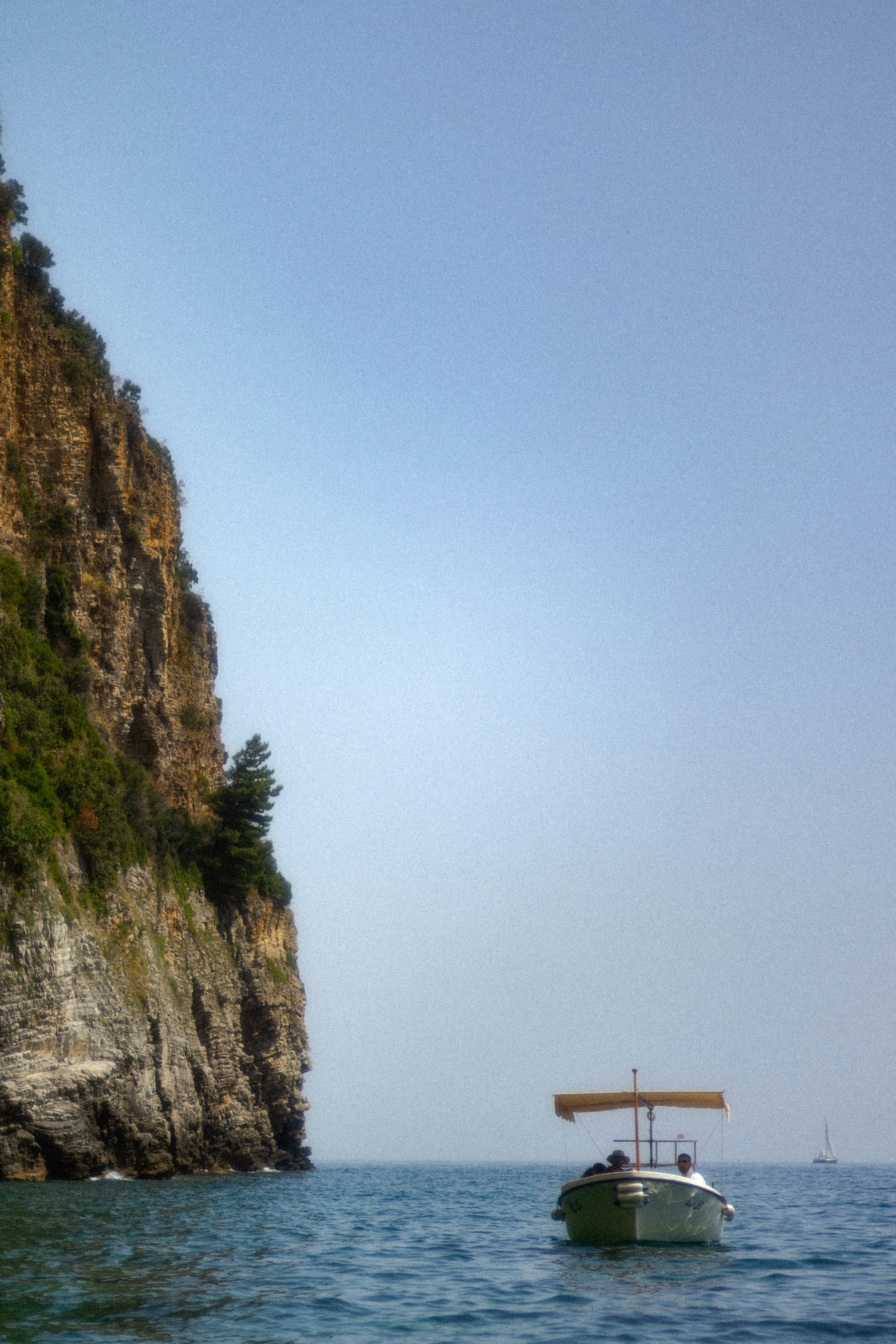 Lone Motorboat Skimming the Blue Between Cliff and Sea