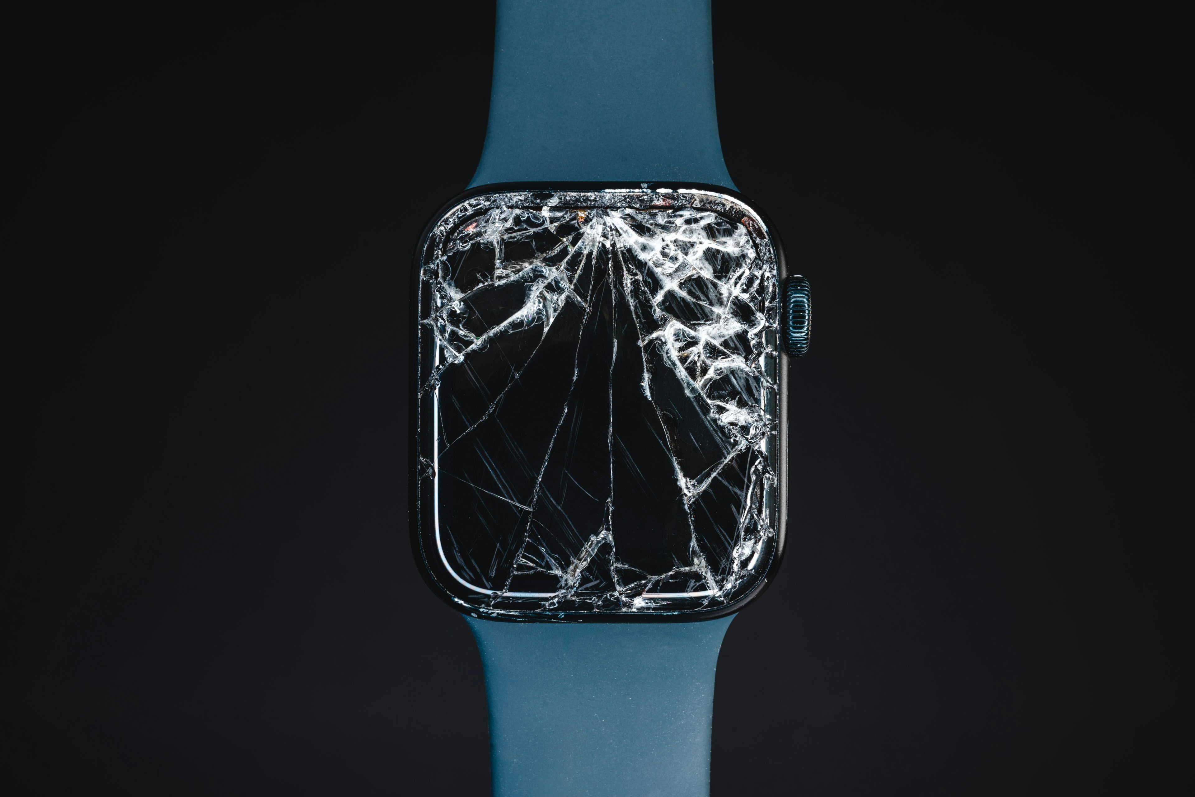 Smartwatch with a shattered screen, showcasing intricate cracks against a dark background.