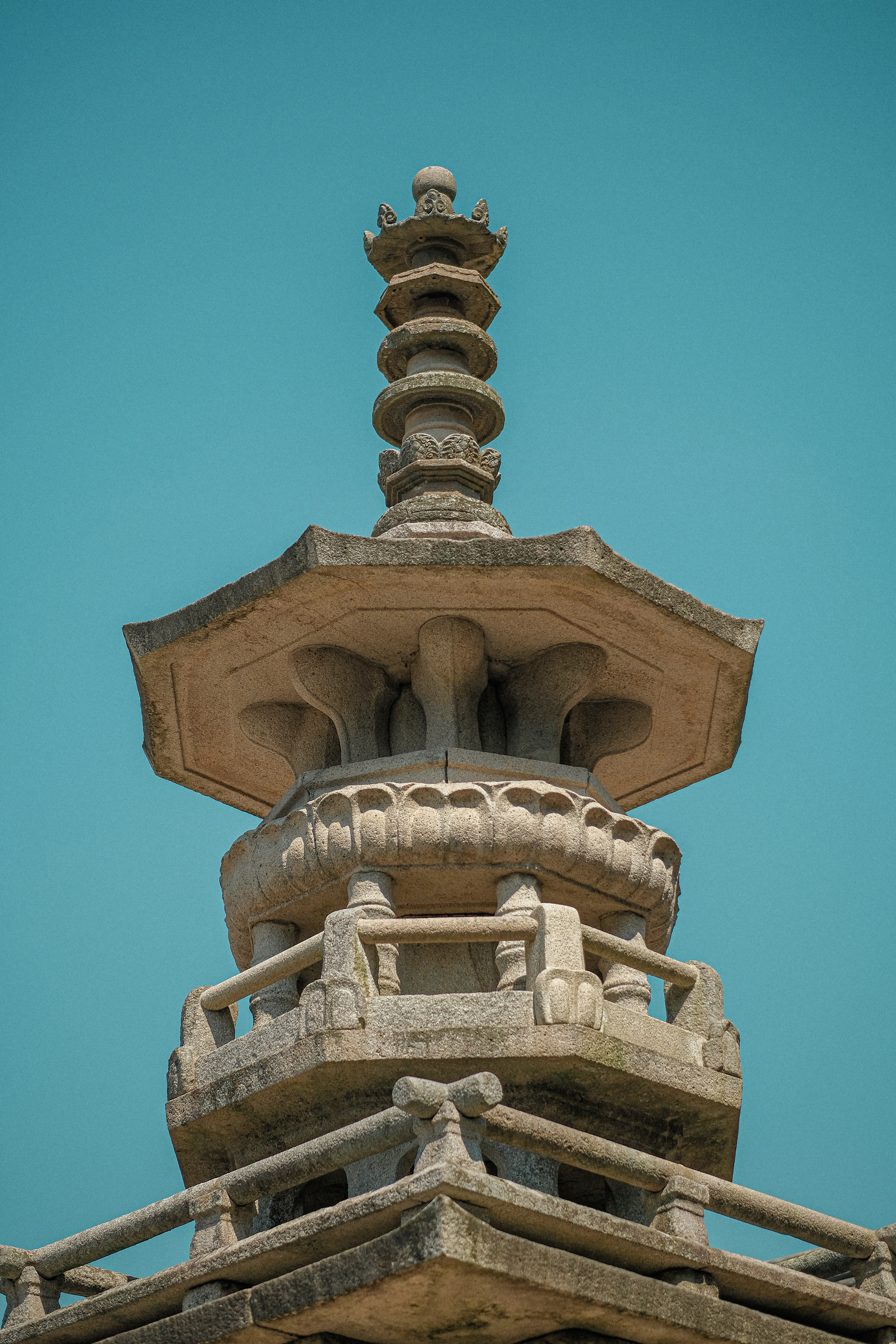 Teal Sky, Silent Spire: A Weathered Stone Pagoda Reaches Up