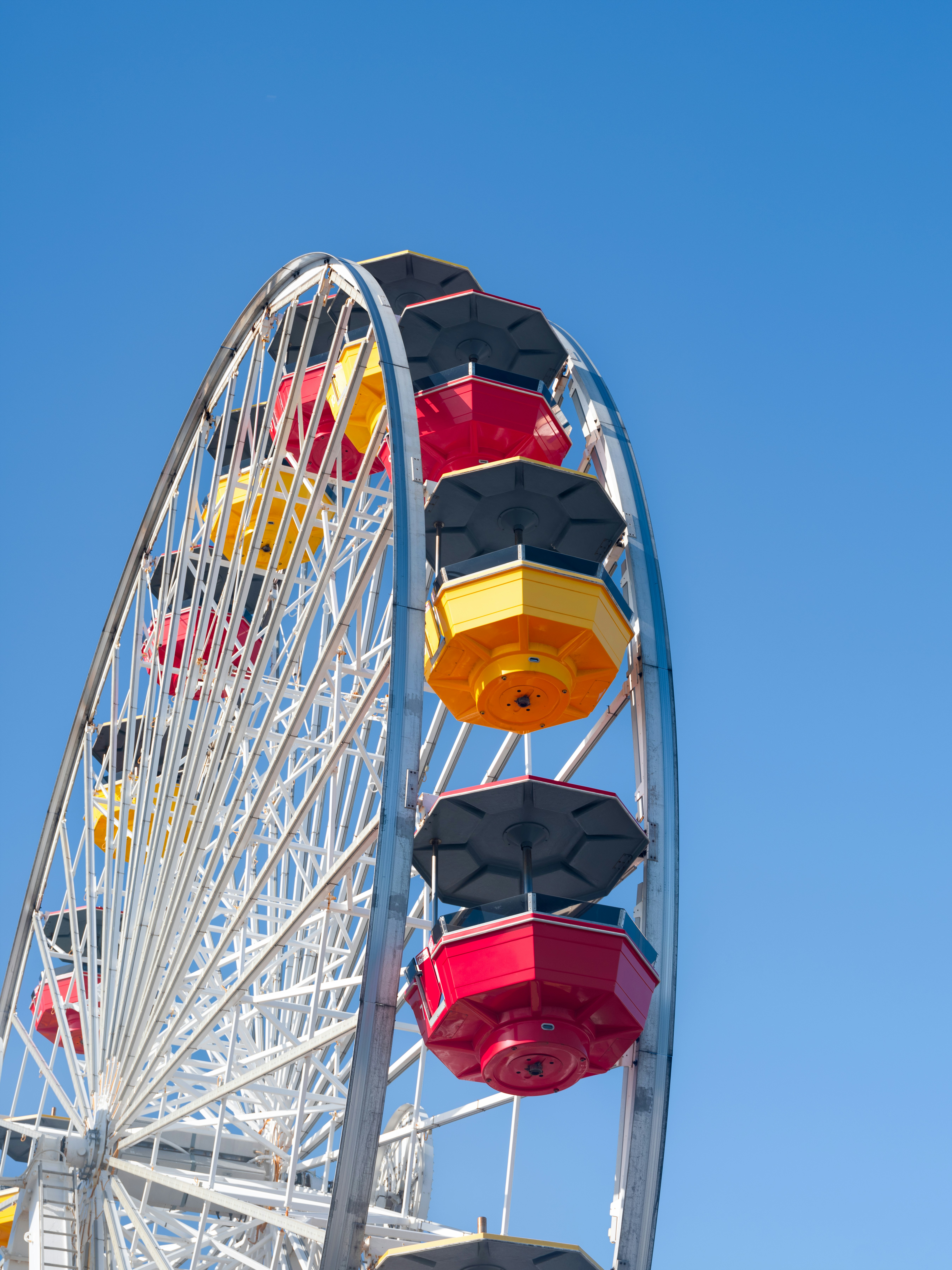 A ferris wheel with colorful seats against a blue sky photo – Free ...