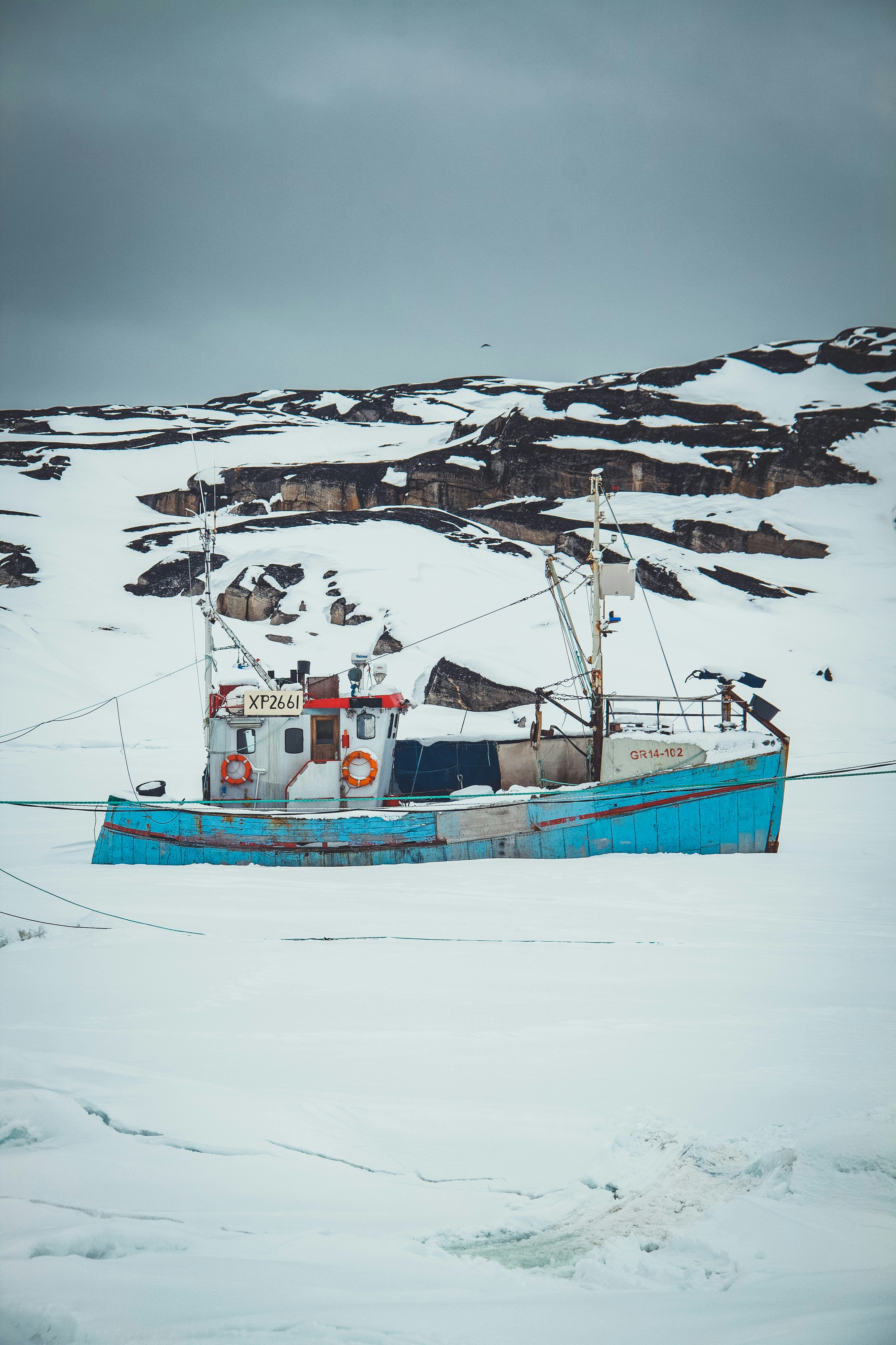 Blue Hull in a Snowbound Fjord: a lone fishing boat amid stark white terrain