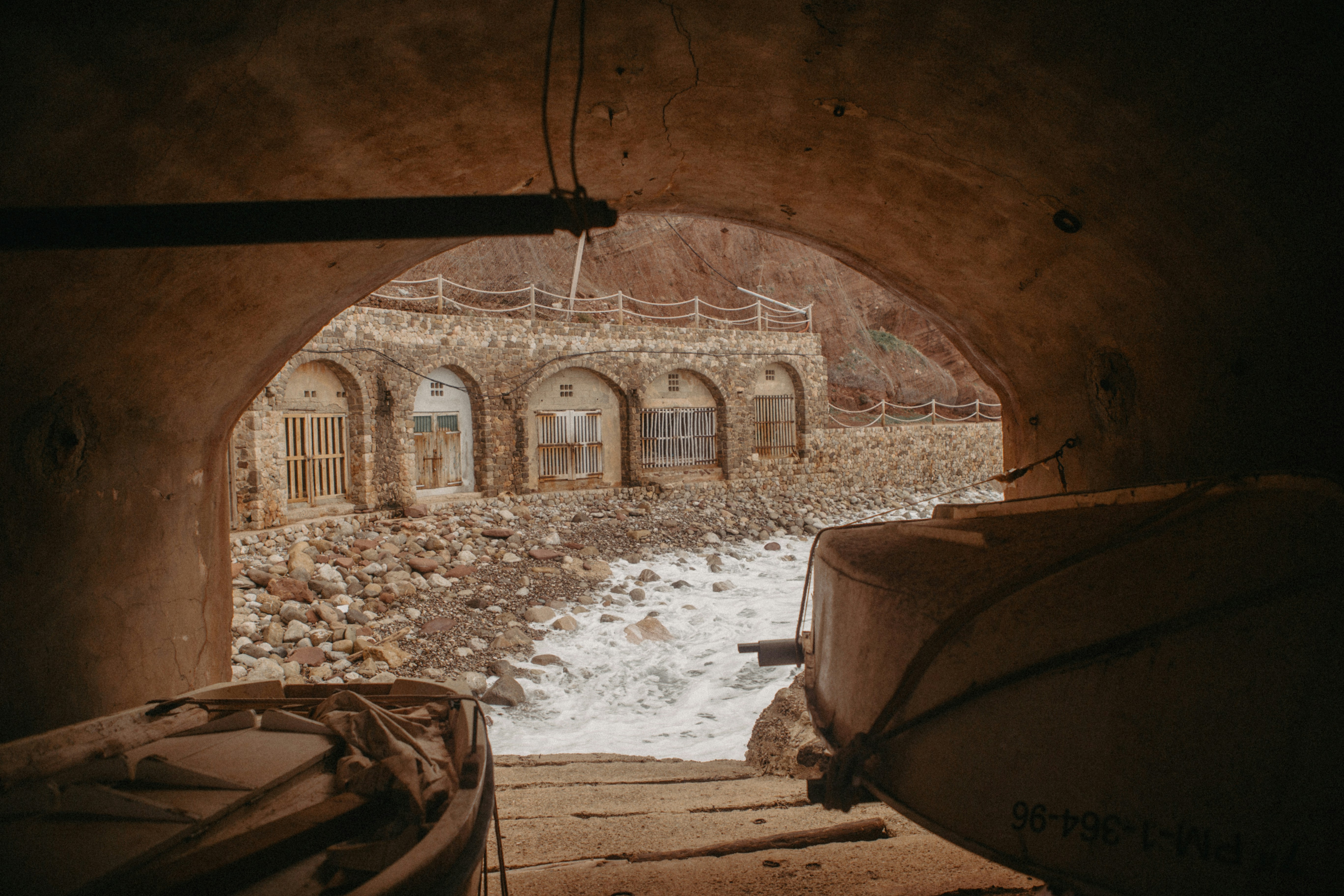 Harbor Archway: Weathered Stone, Quiet Tide, and Wooden Boats