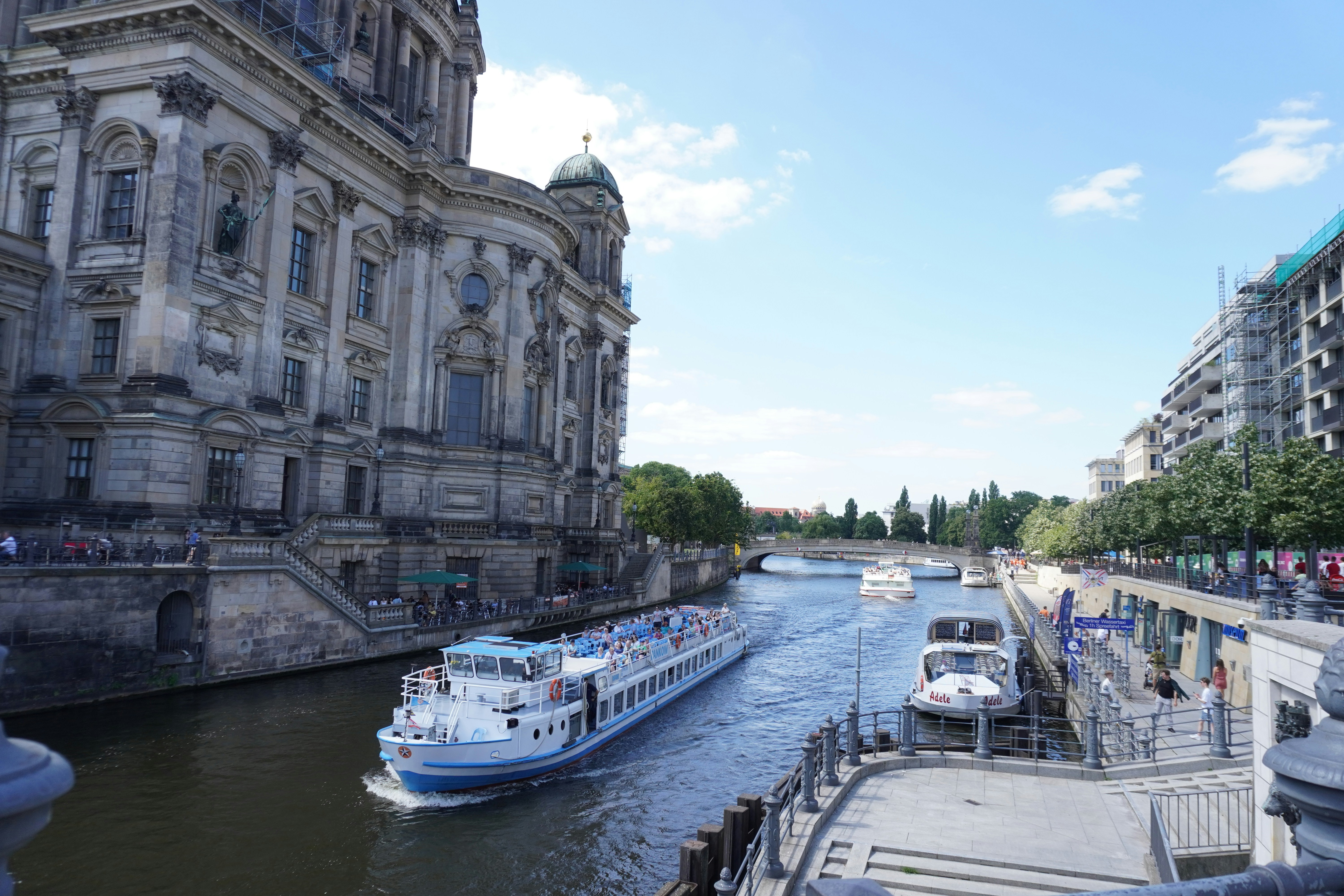 White Tour Boat Glides Past Baroque Facades on a Sunlit City Canal