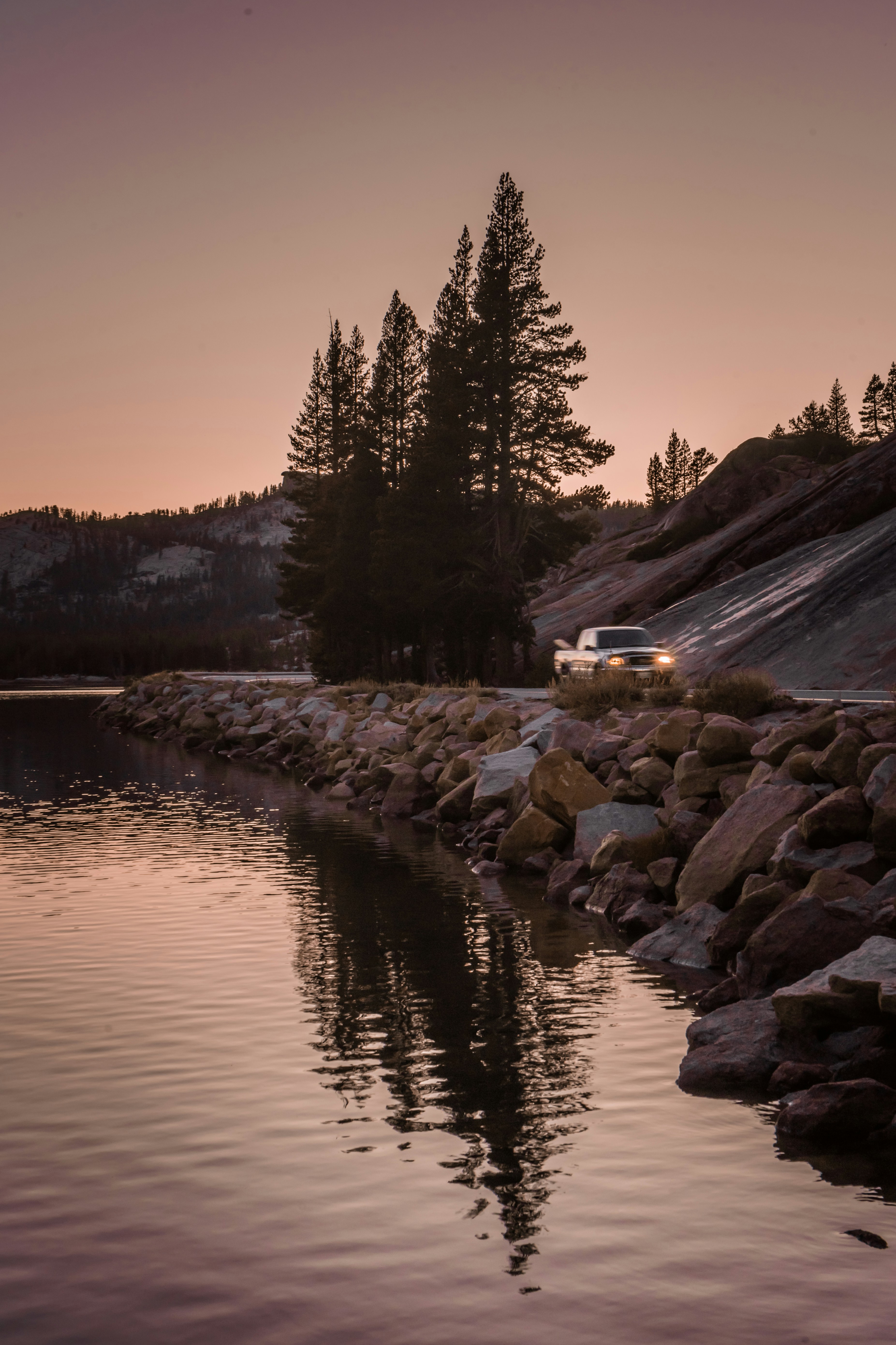 Evening Drive Along a Rugged Lakeside Road Under Silent Pines