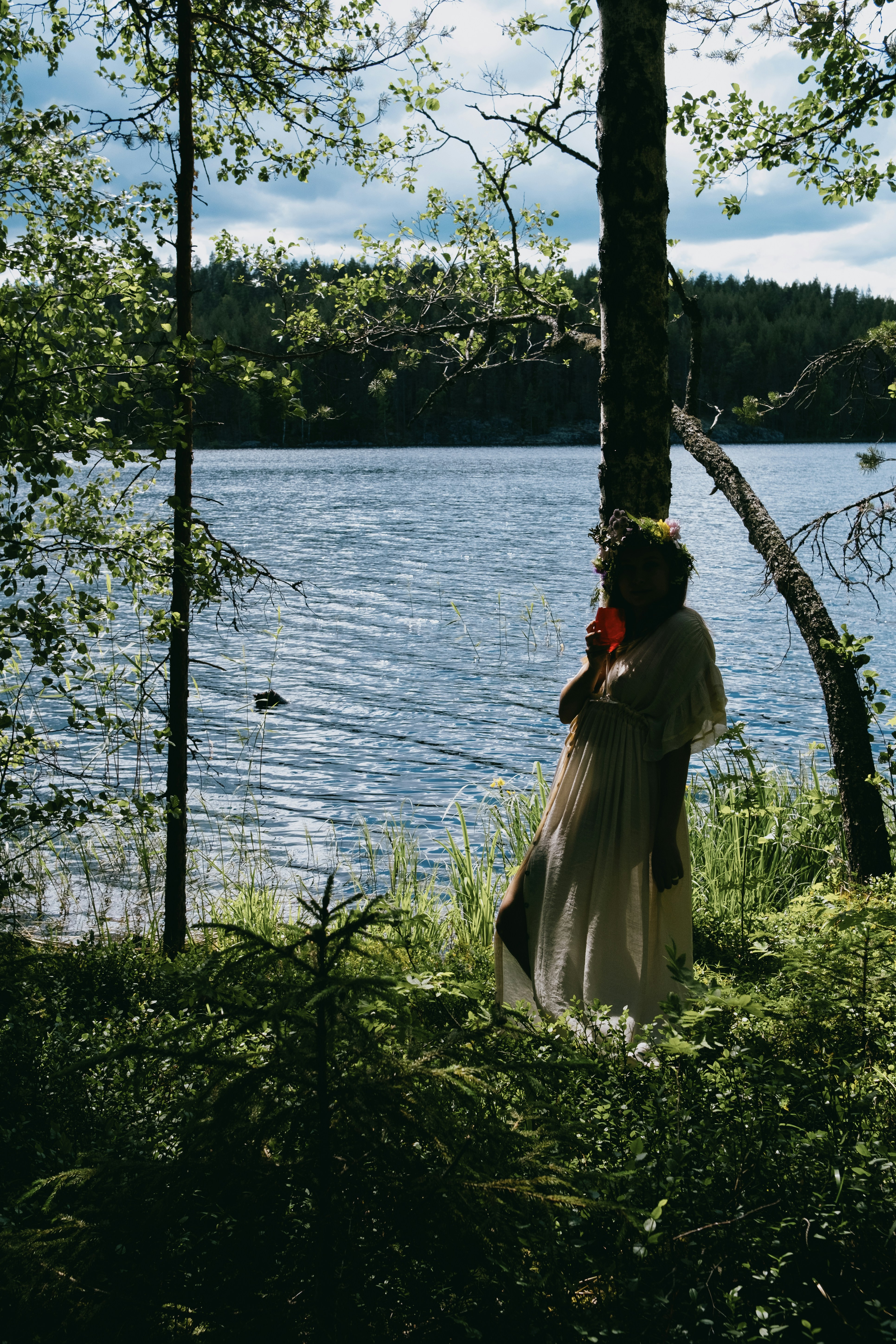 Lakeside Veil: A Figure in White Framed by Sunlit Water and Trees