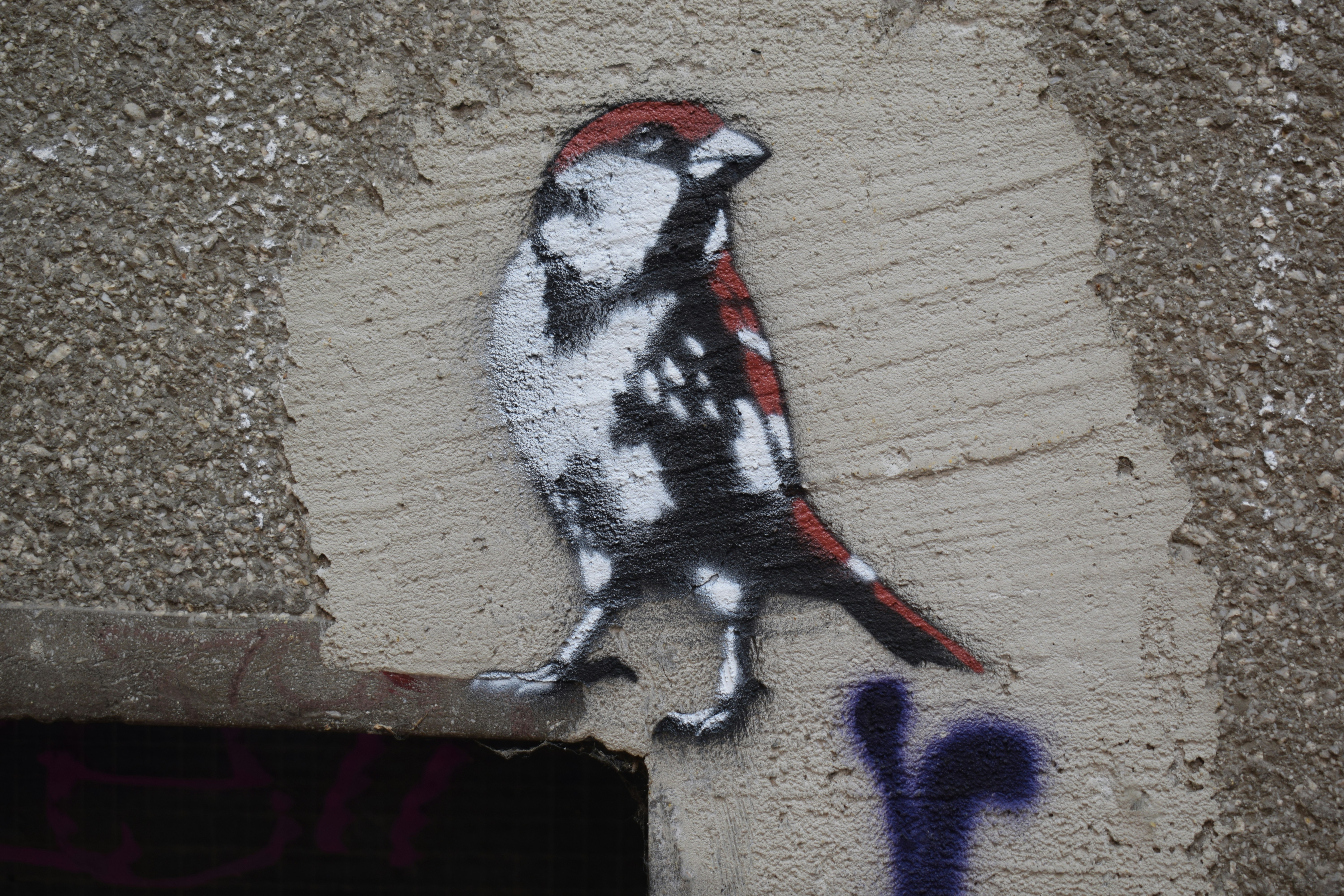 Urban Cardinal Graffiti: A Crimson-Capped Stencil on Weathered Concrete