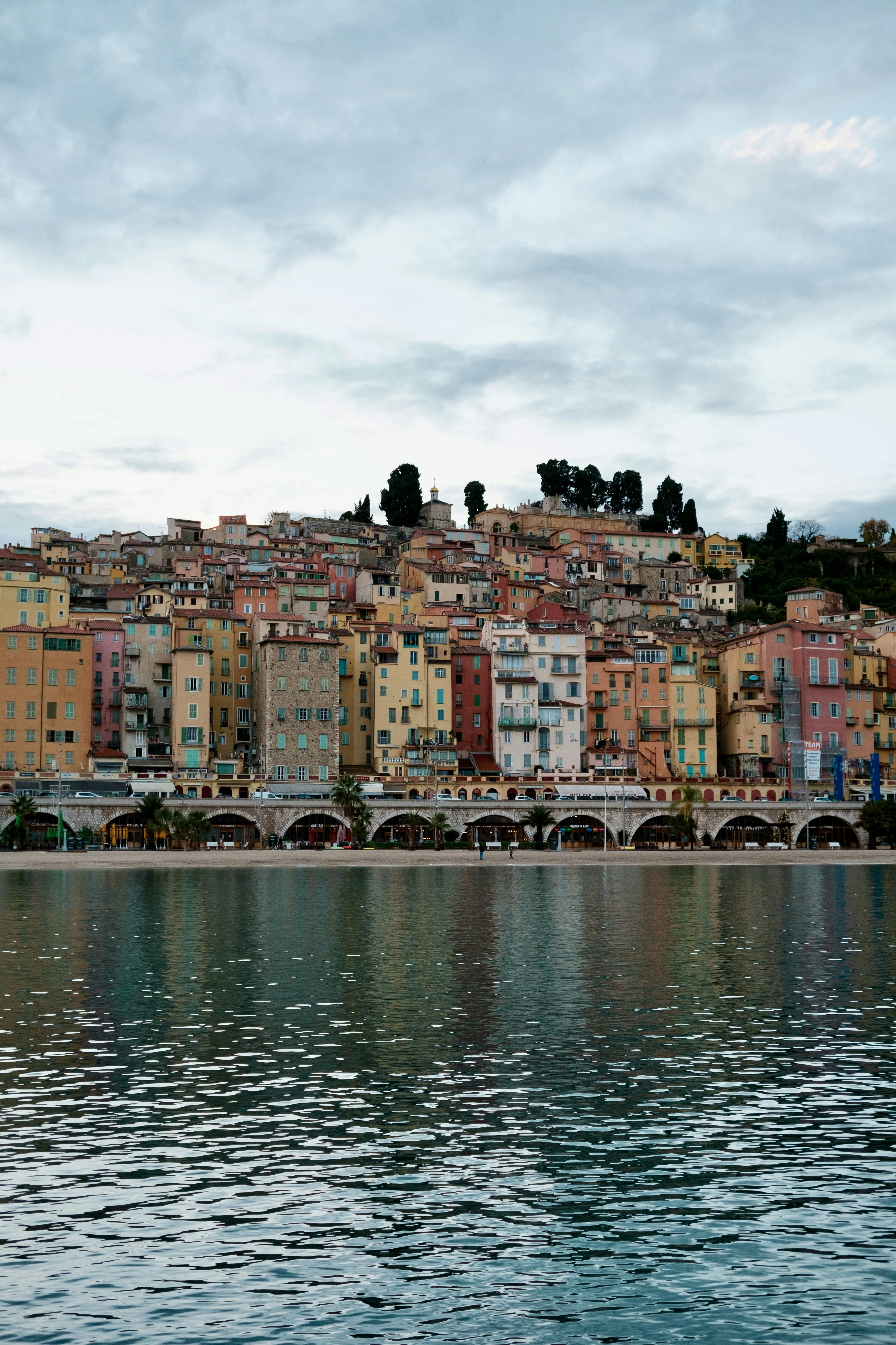 Pastel Harbor: Arched waterfronts cradle a colorful hillside town
