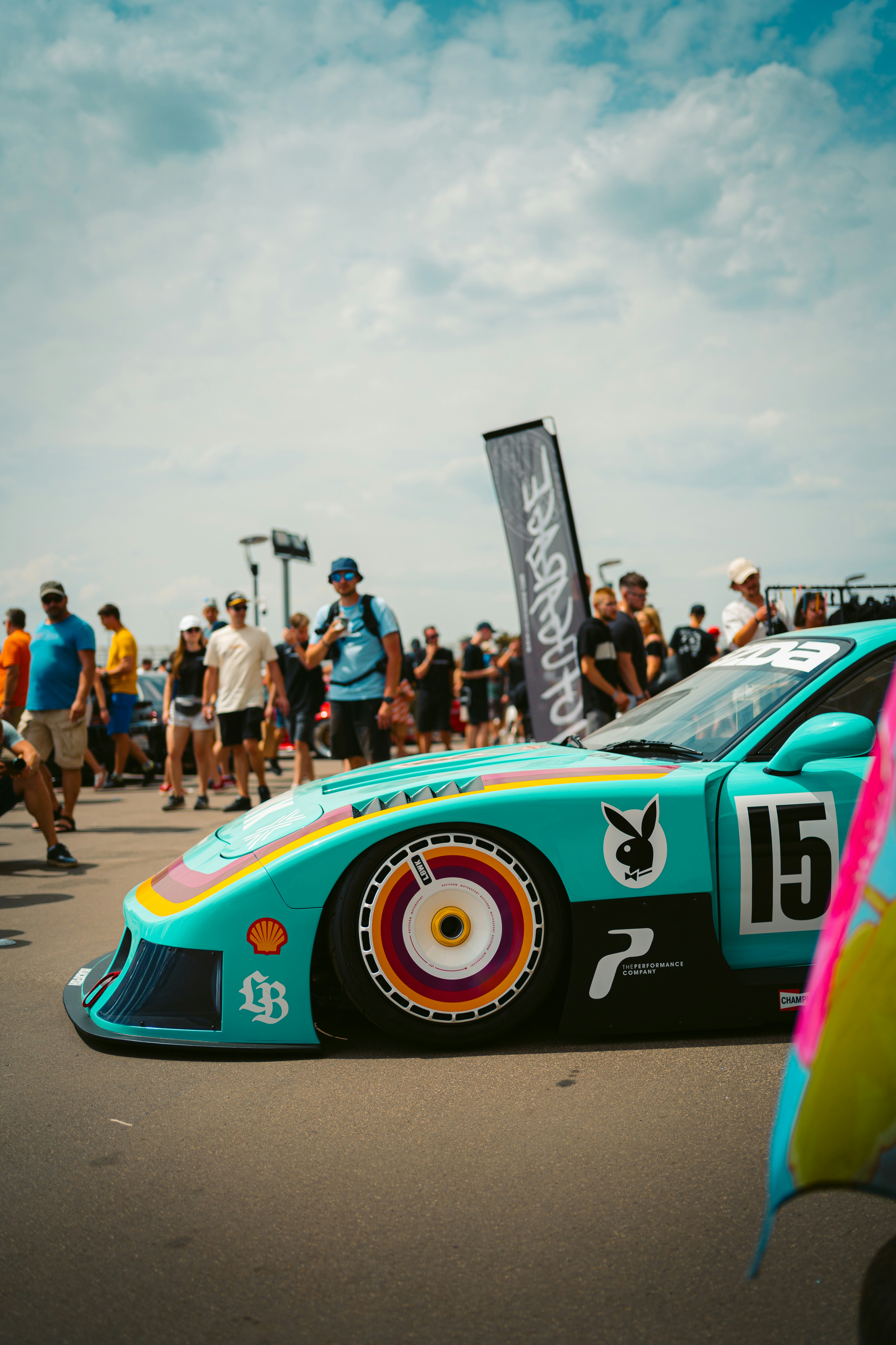 Teal Thunder at the Paddock: A Rainbow-Trim Race Car Among a Crowded Grid