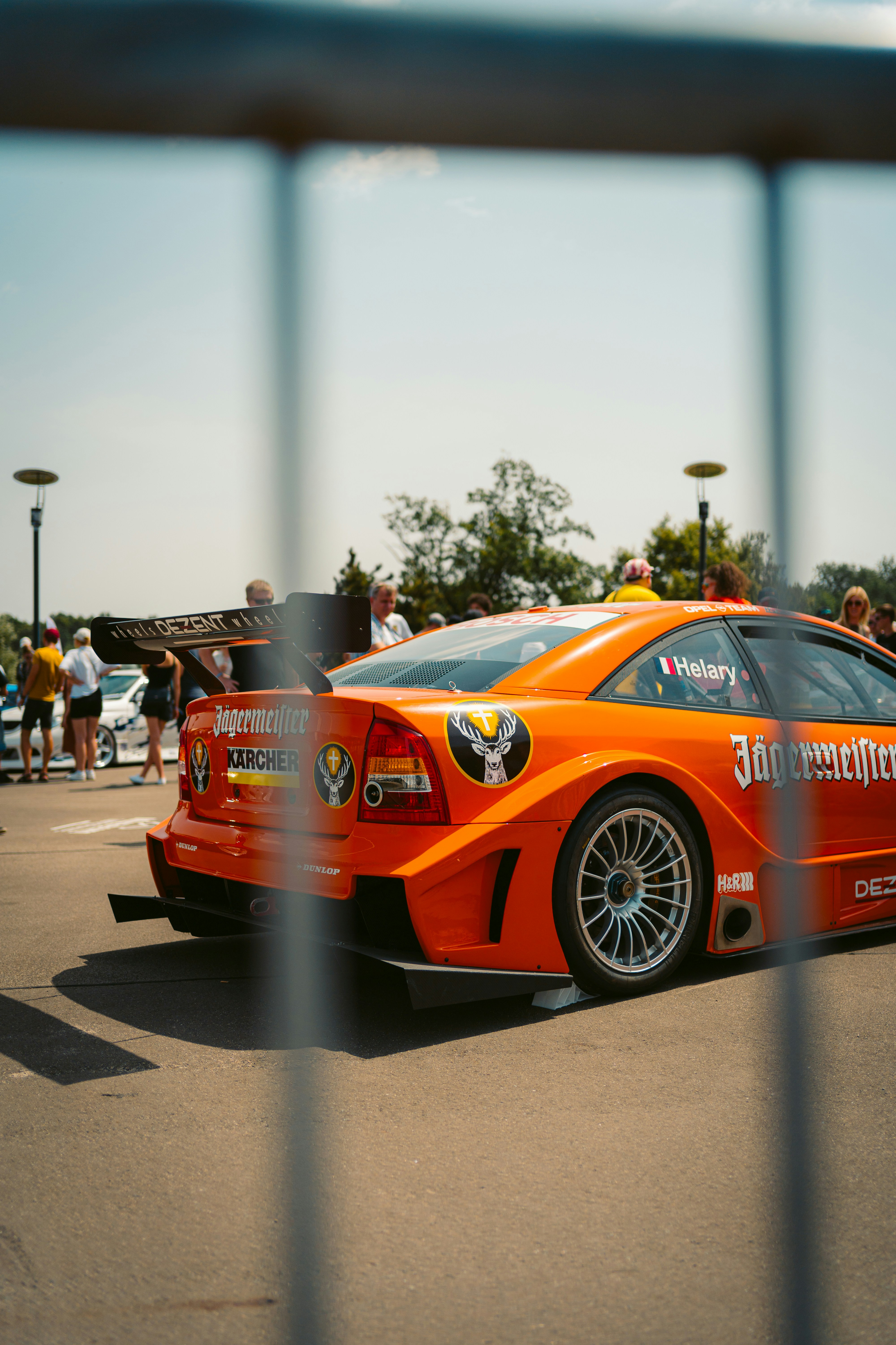 An orange race car is parked in a parking lot photo – Free Stadion ...