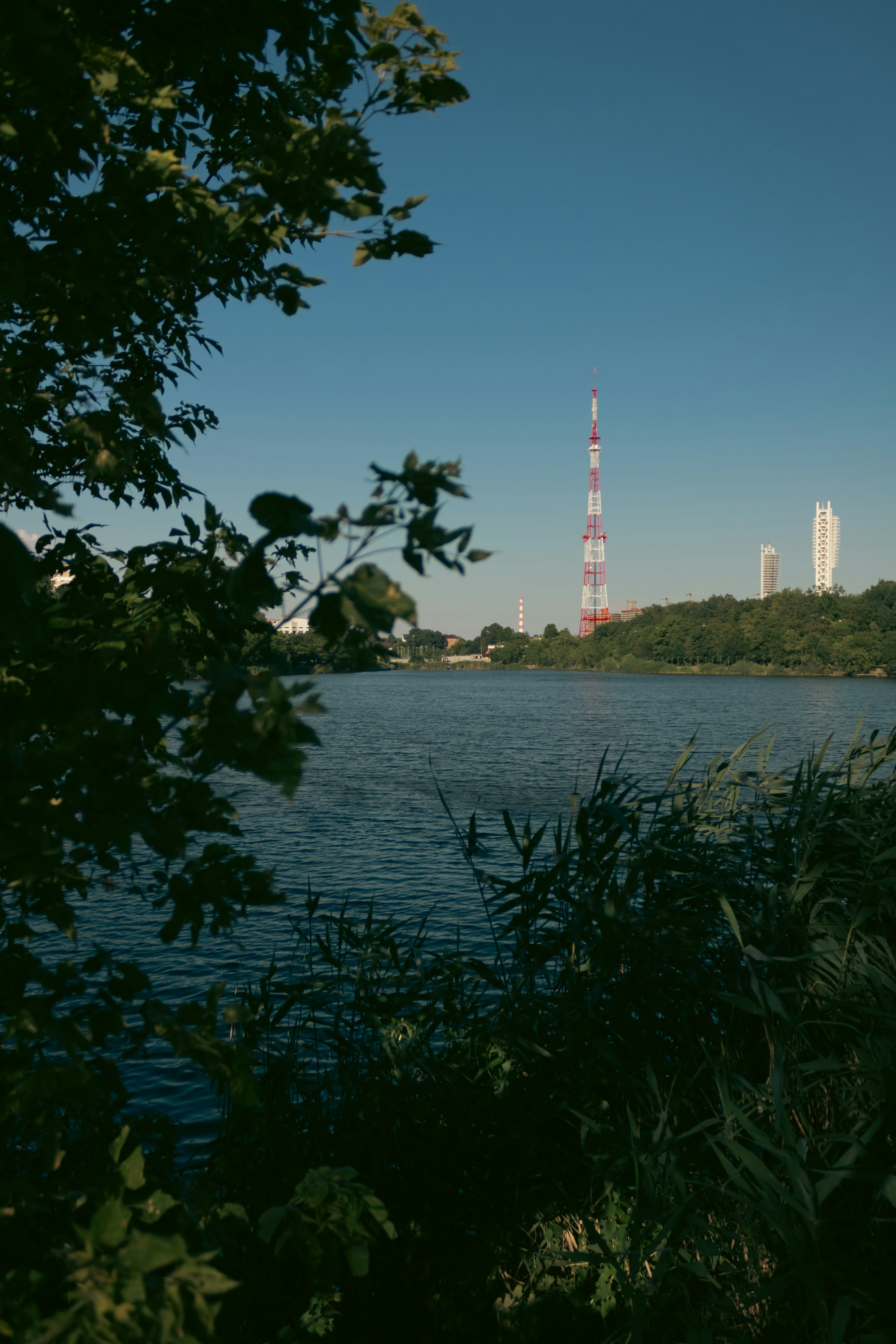 Sentinel Over the Quiet Lake: A Red-and-White Tower Framed by Green Riverside