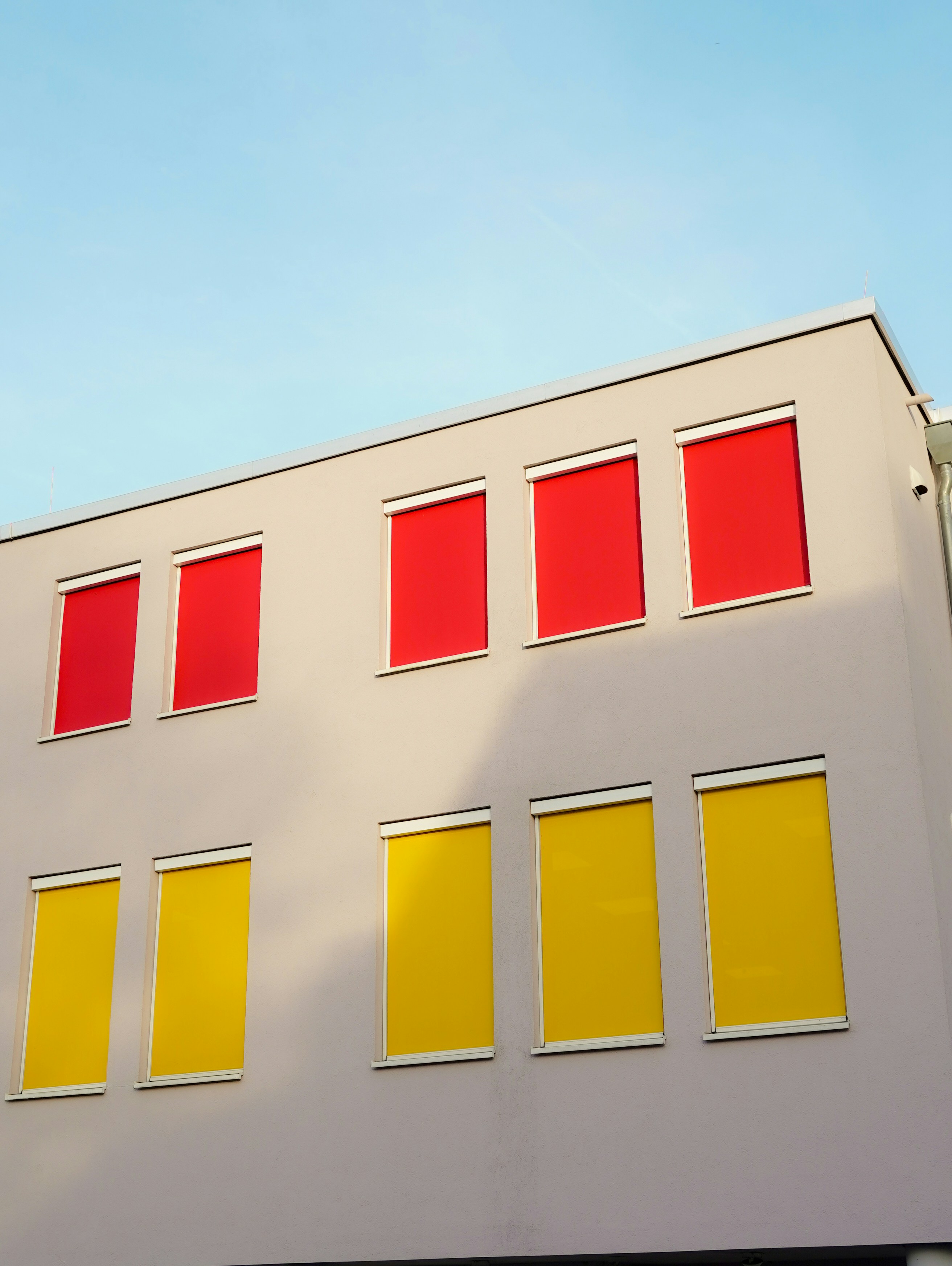 A white building with red and yellow windows photo – Free Building ...