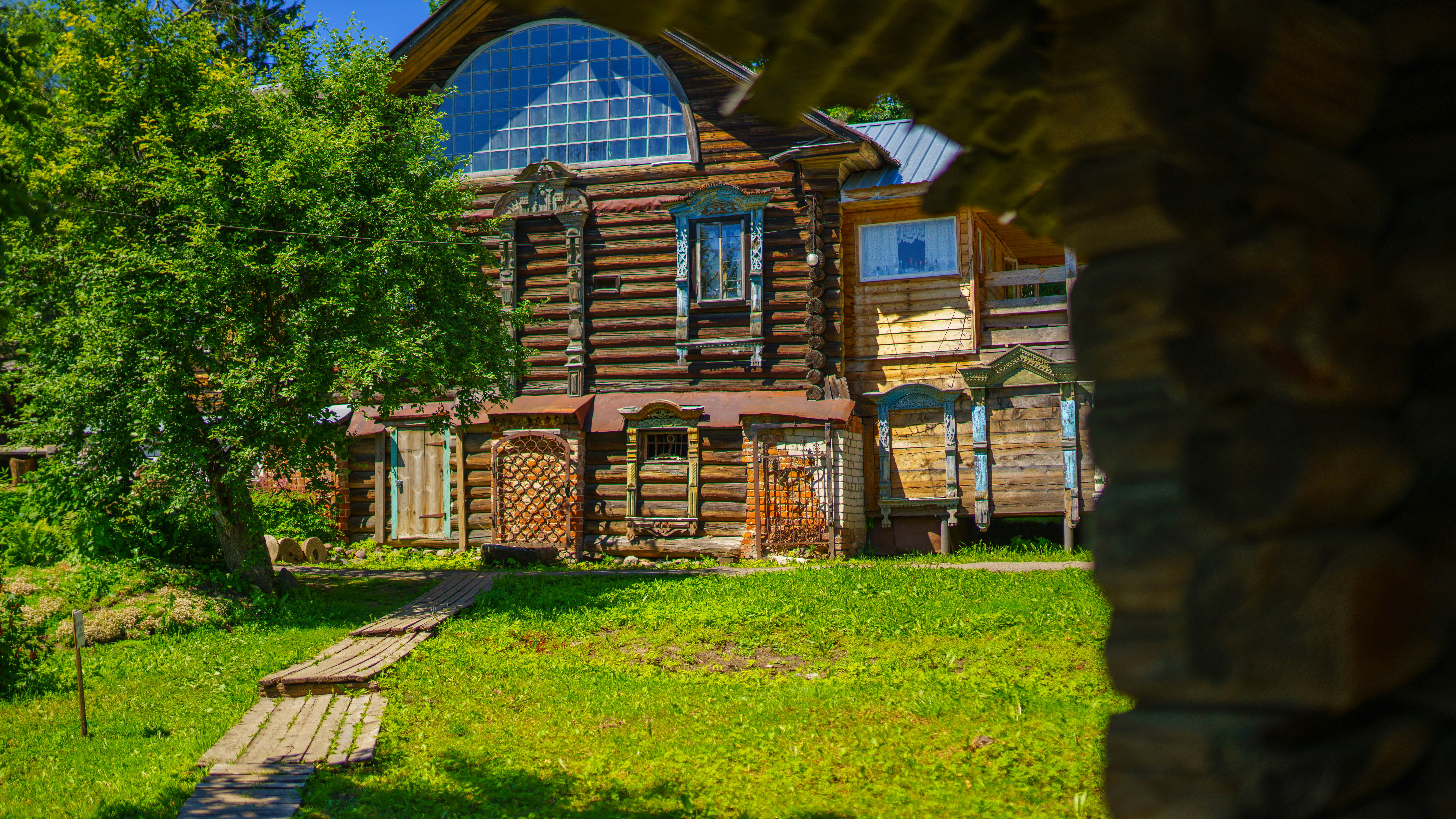 Arched Window, Green Lawn: A Rustic Log Cabin in Daylight