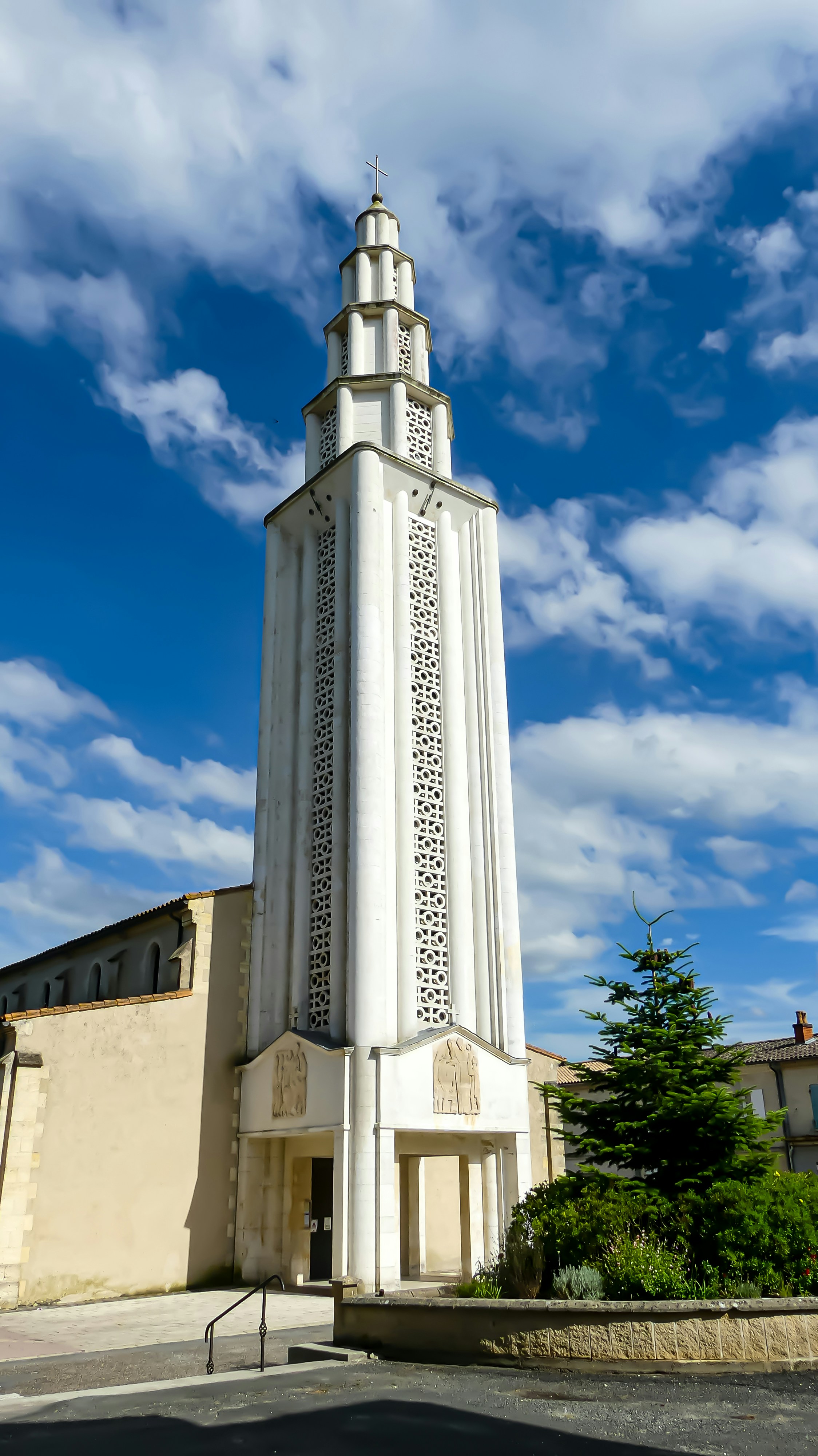Vertical Ascension: A pale spire rises beside a sunlit courtyard under a bright blue sky