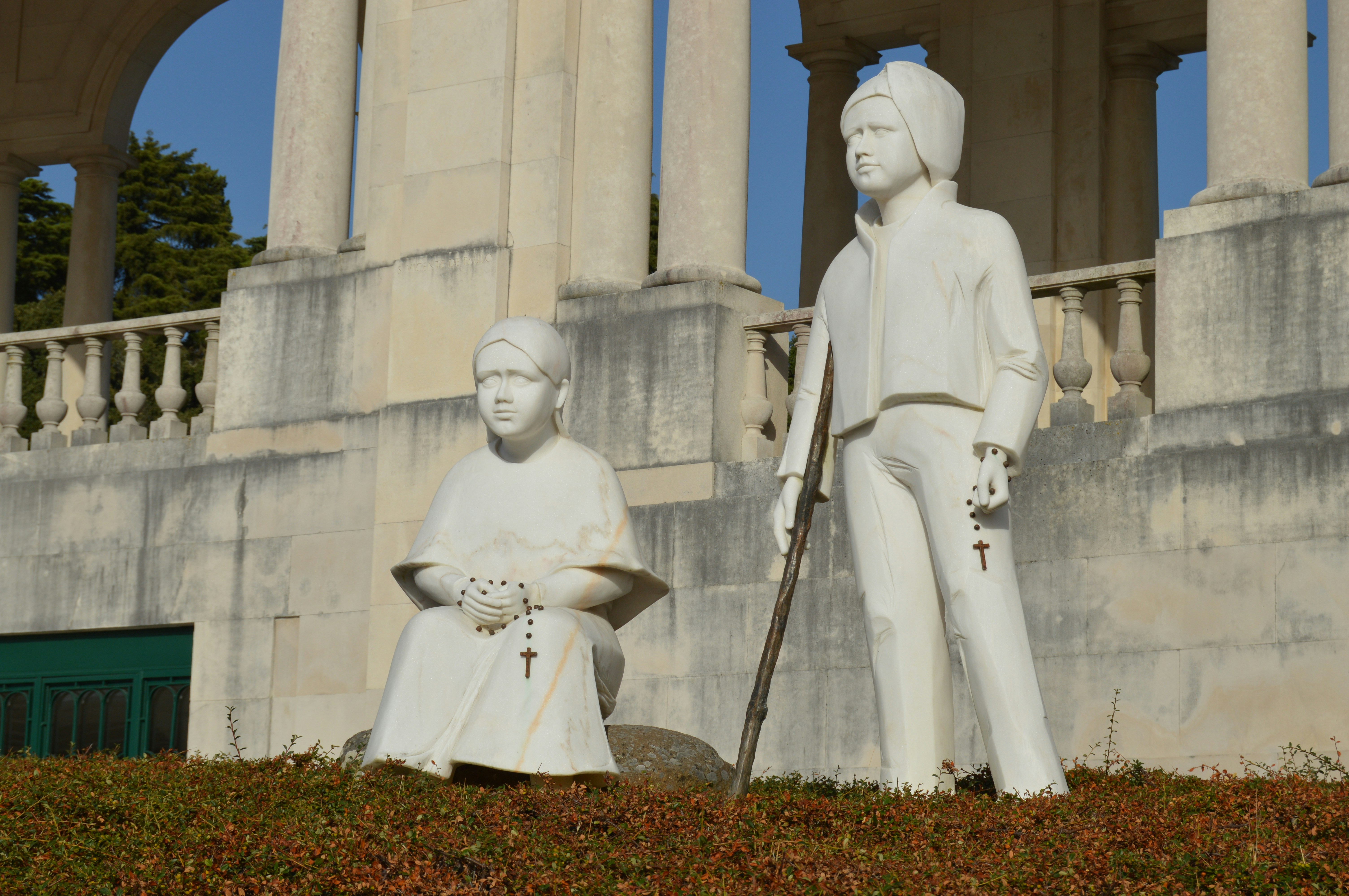 Guardians on the Terrace: Marble Statues Beside the Pillared Shrine