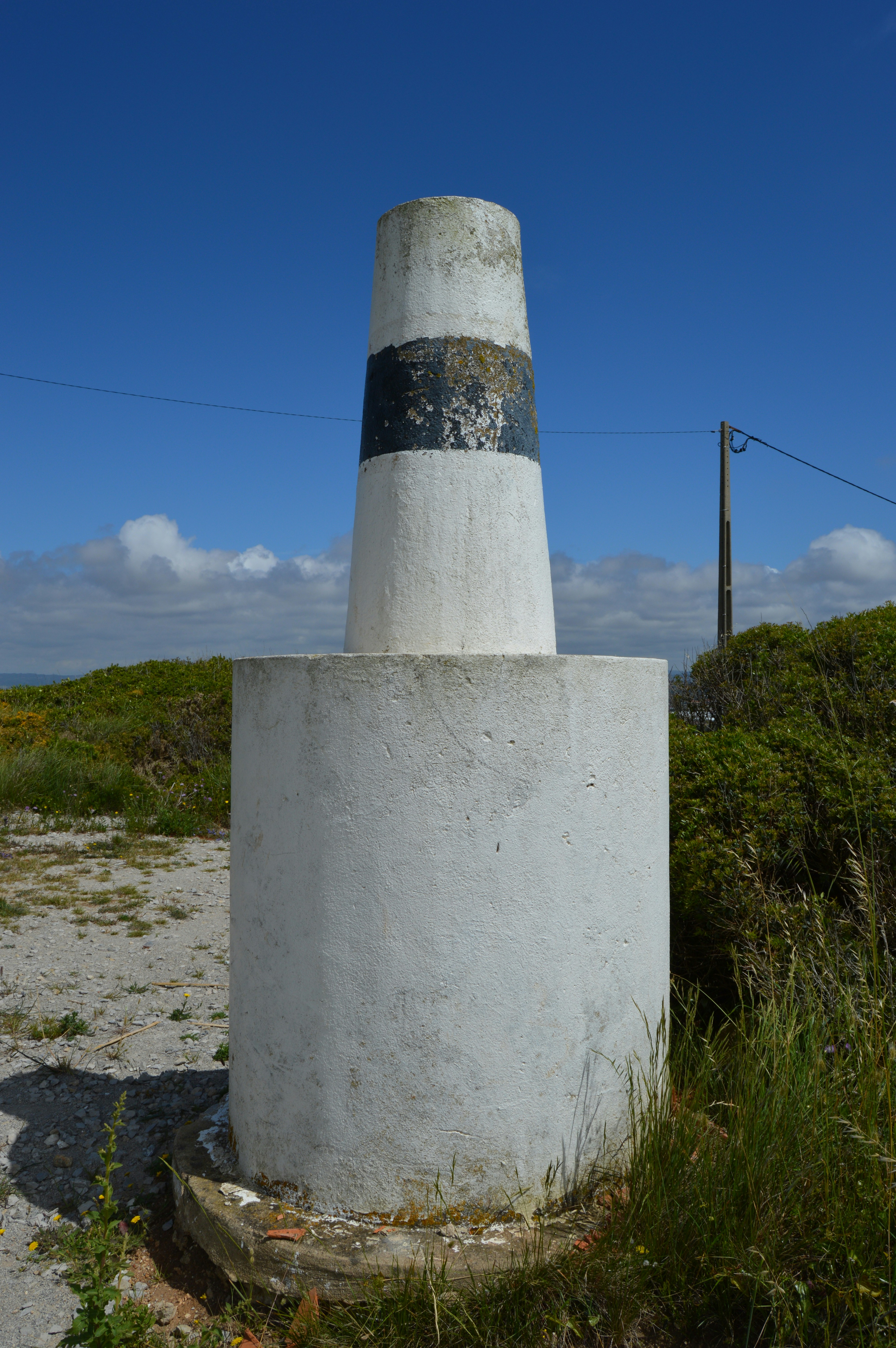 Coastal Marker Rising: Weathered White Pillar with a Dark Band
