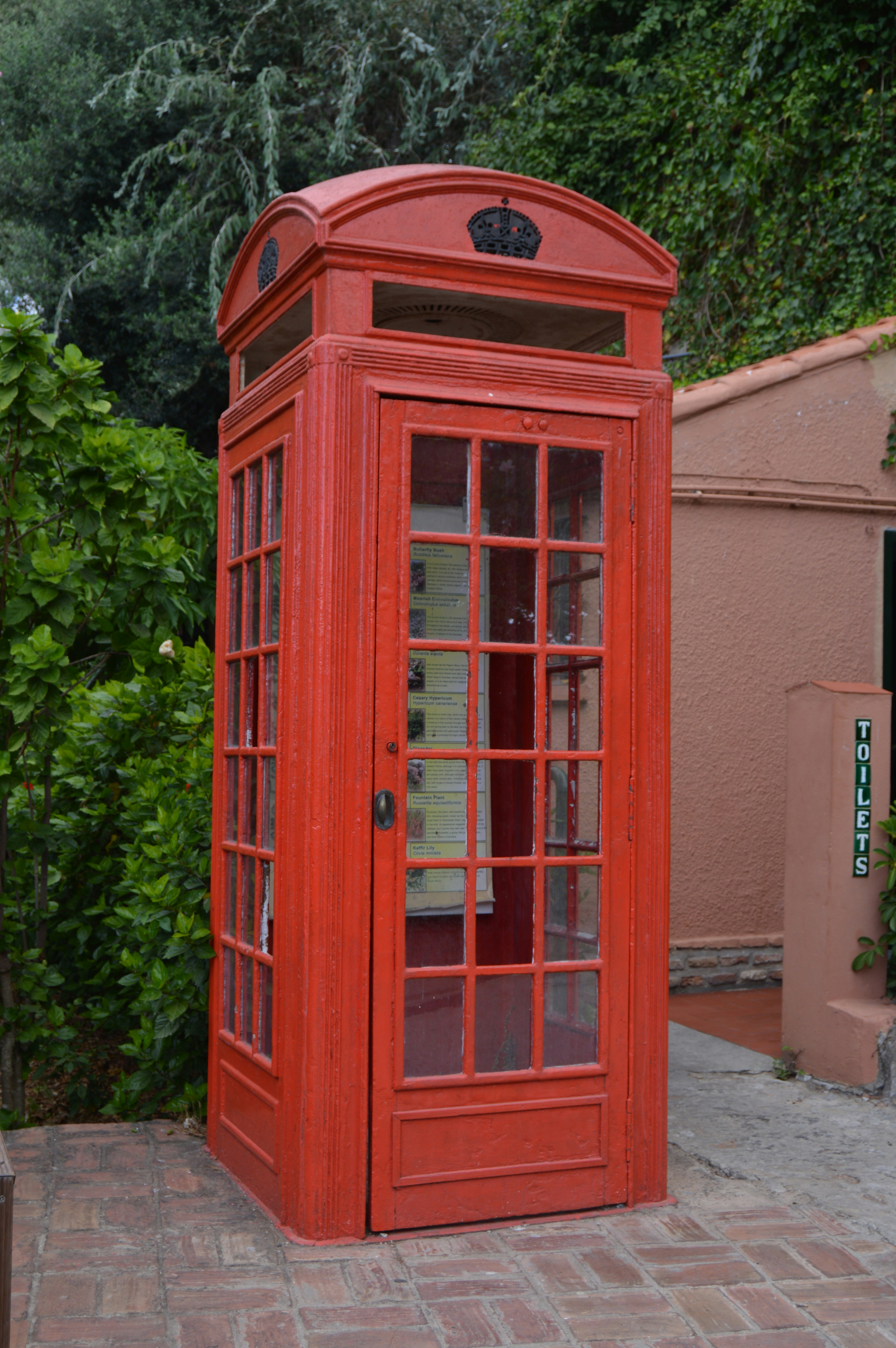 Crimson Kiosk Standing Guard in a Quiet Courtyard