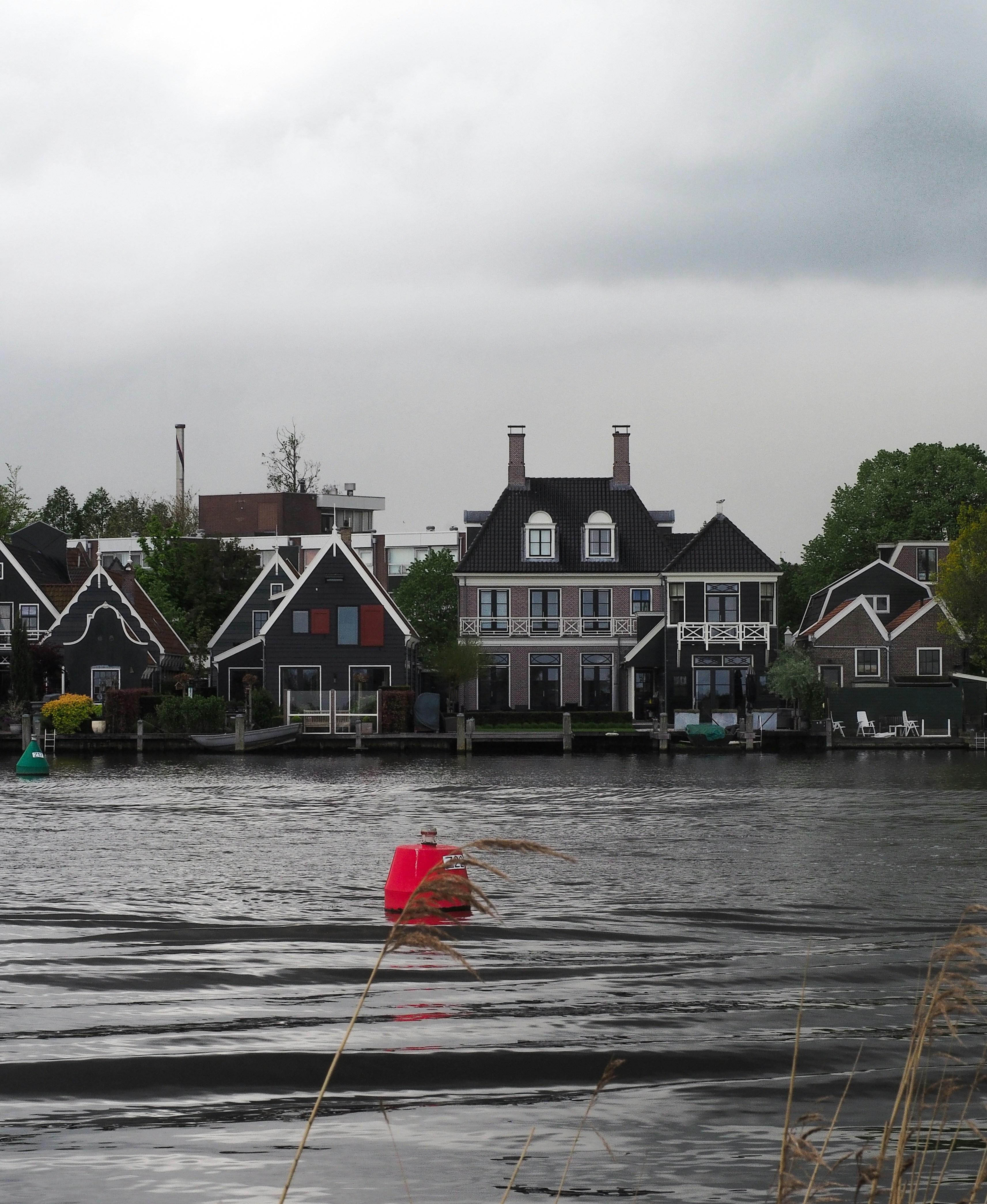 Red Buoy Over Calm Canalfront: Gabled Houses and Ripples