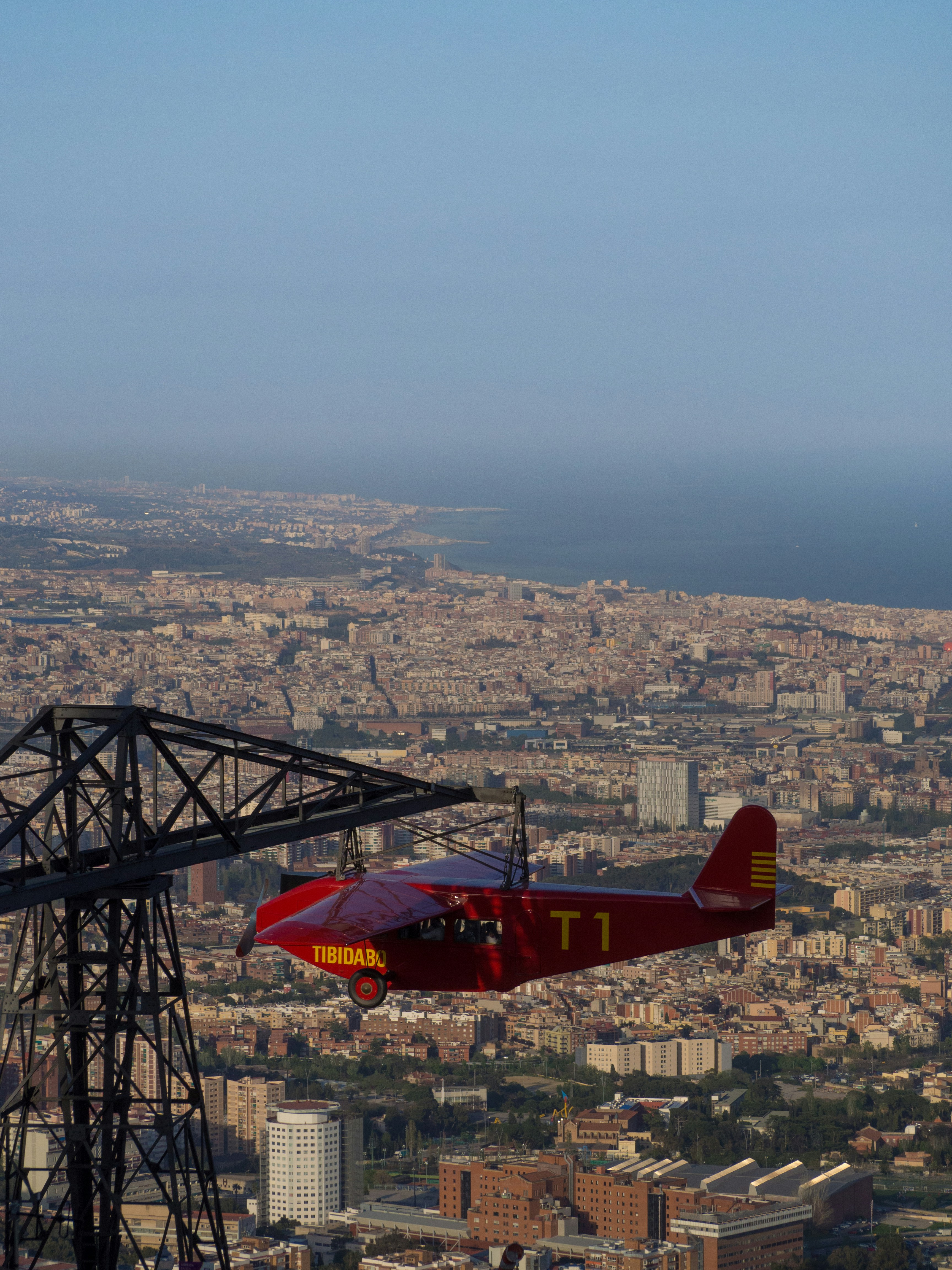 A small red plane flying over a city photo – Free Urban Image on Unsplash
