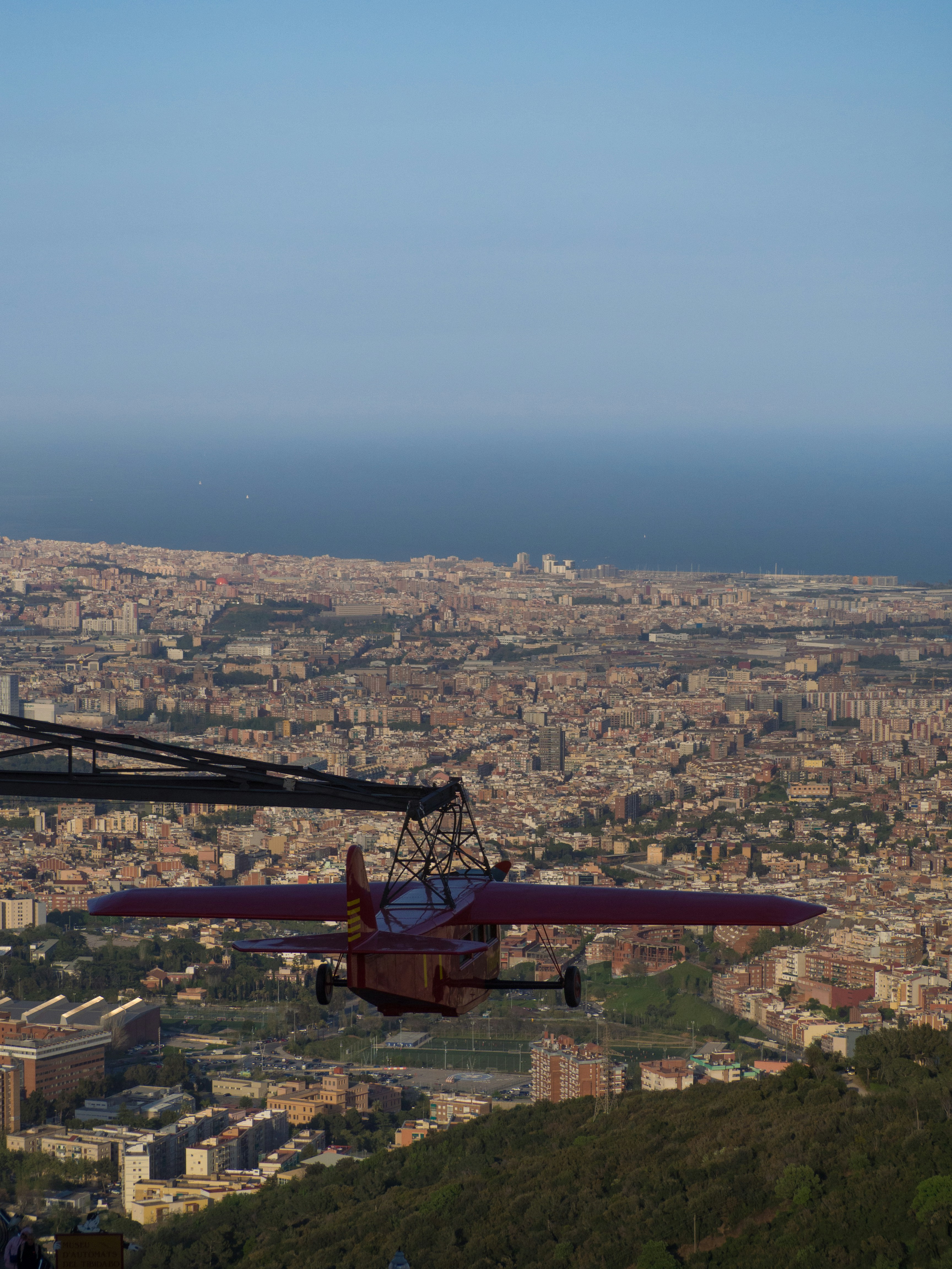 Red High-Wing Plane Over a Sprawling Coastal City