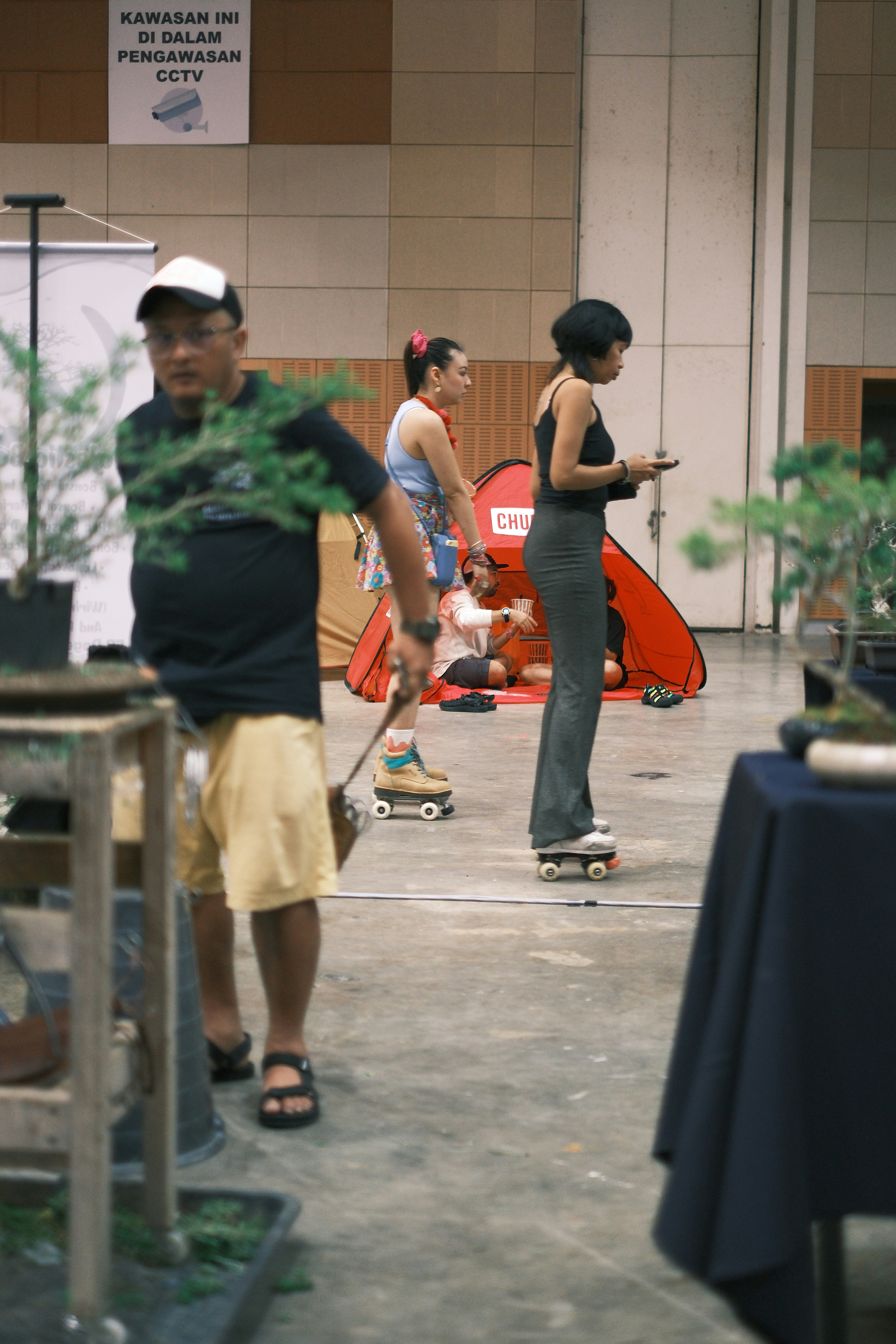 Skater in Steel-Gray: A Quiet Moment Amid Indoor Expo Activity