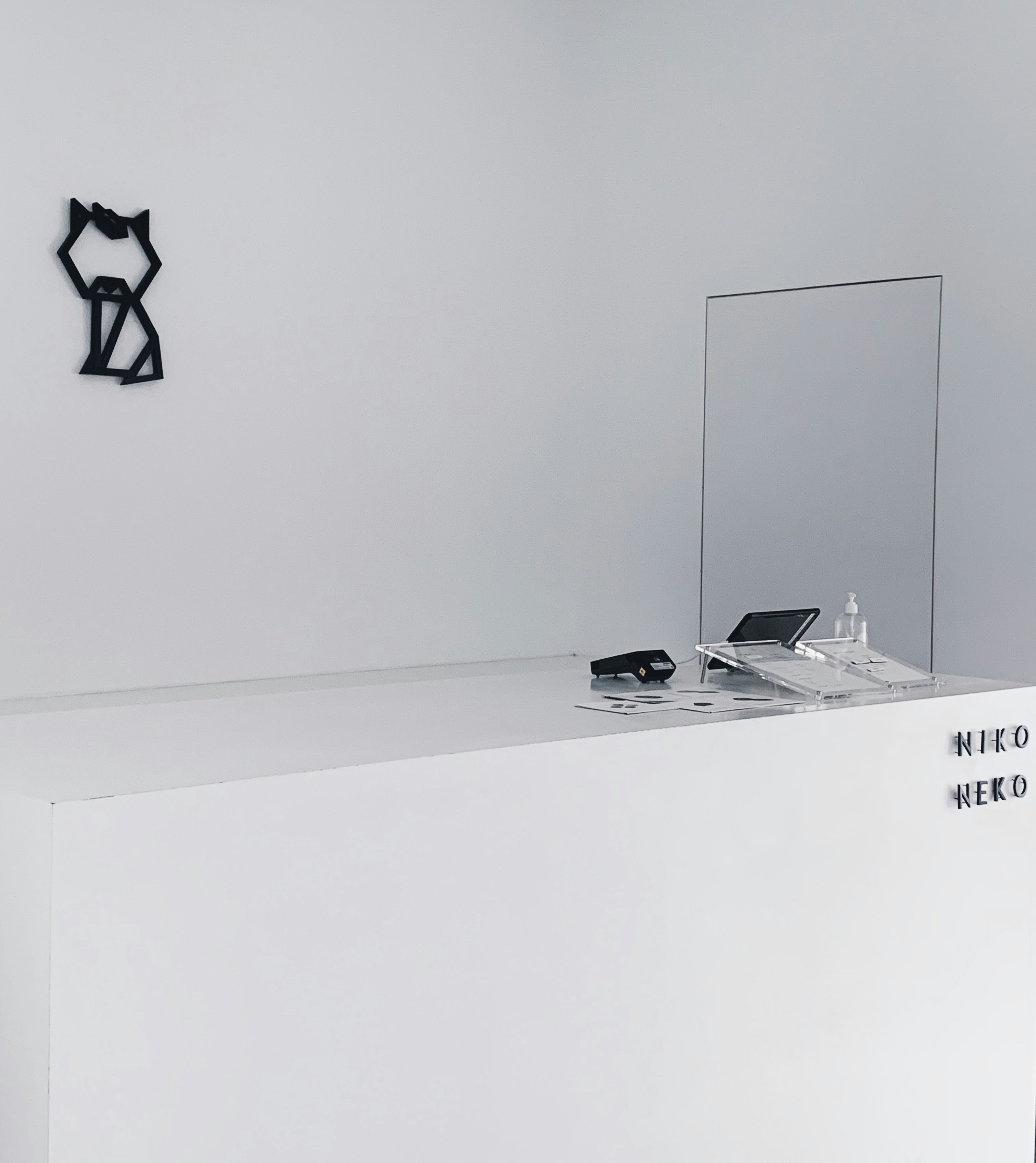 Sterile White Showroom: A Minimal Counter with Sleek Tech and a Black Cat Wall Sculpture