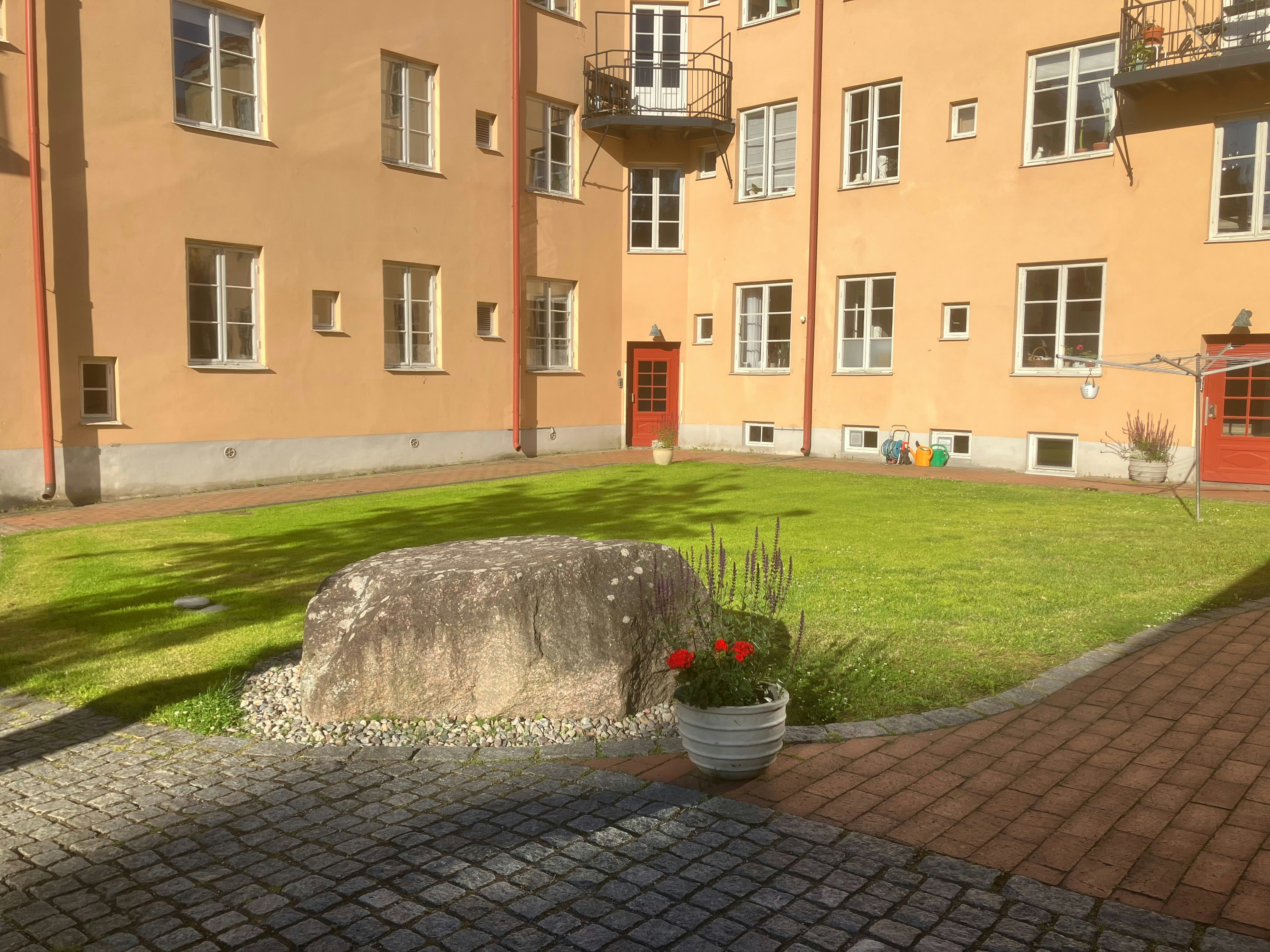 Sunlit Courtyard Rock Framed by Peach Buildings and Red Doors