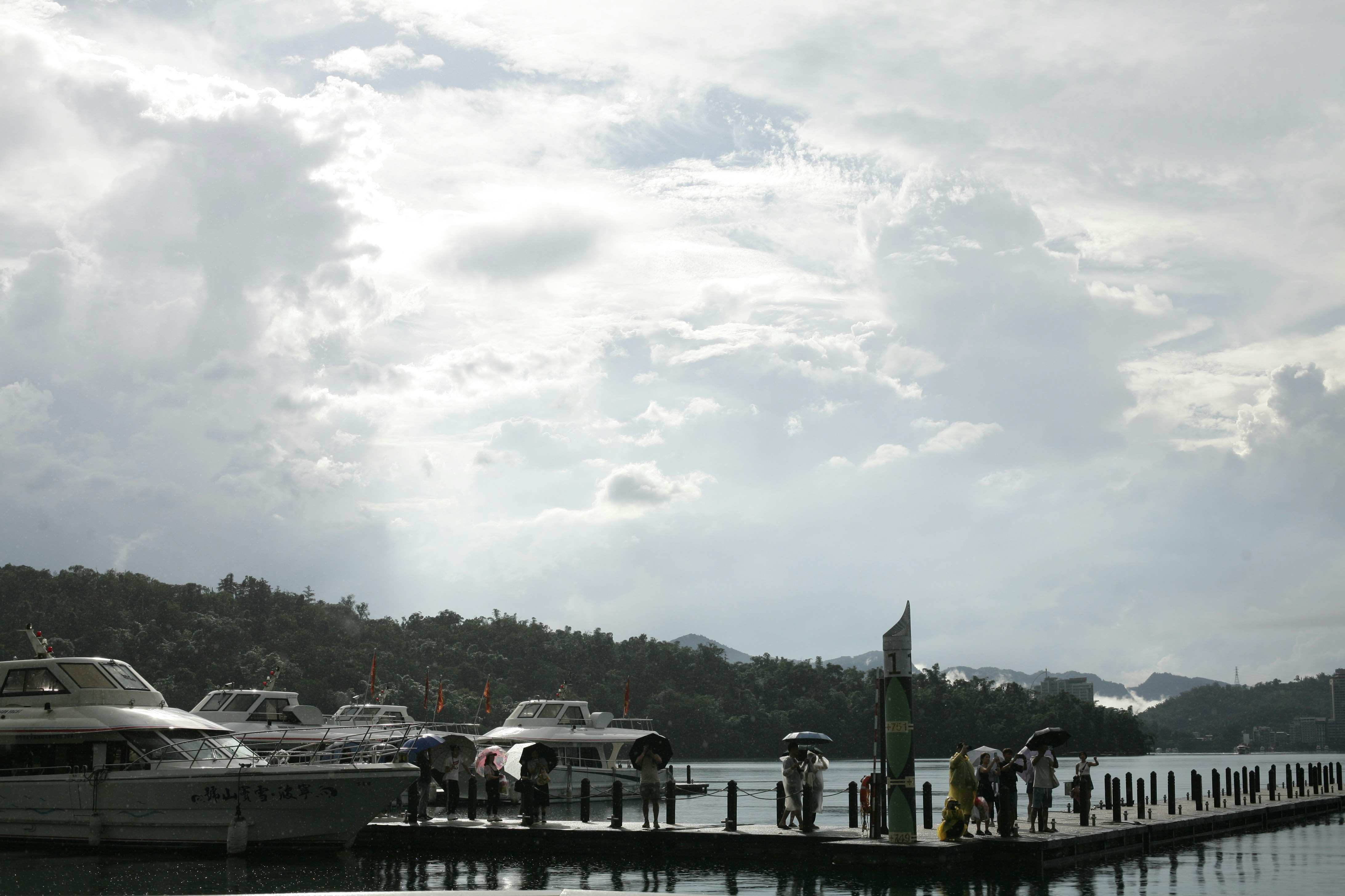 A group of people standing on a dock next to a body of water photo ...