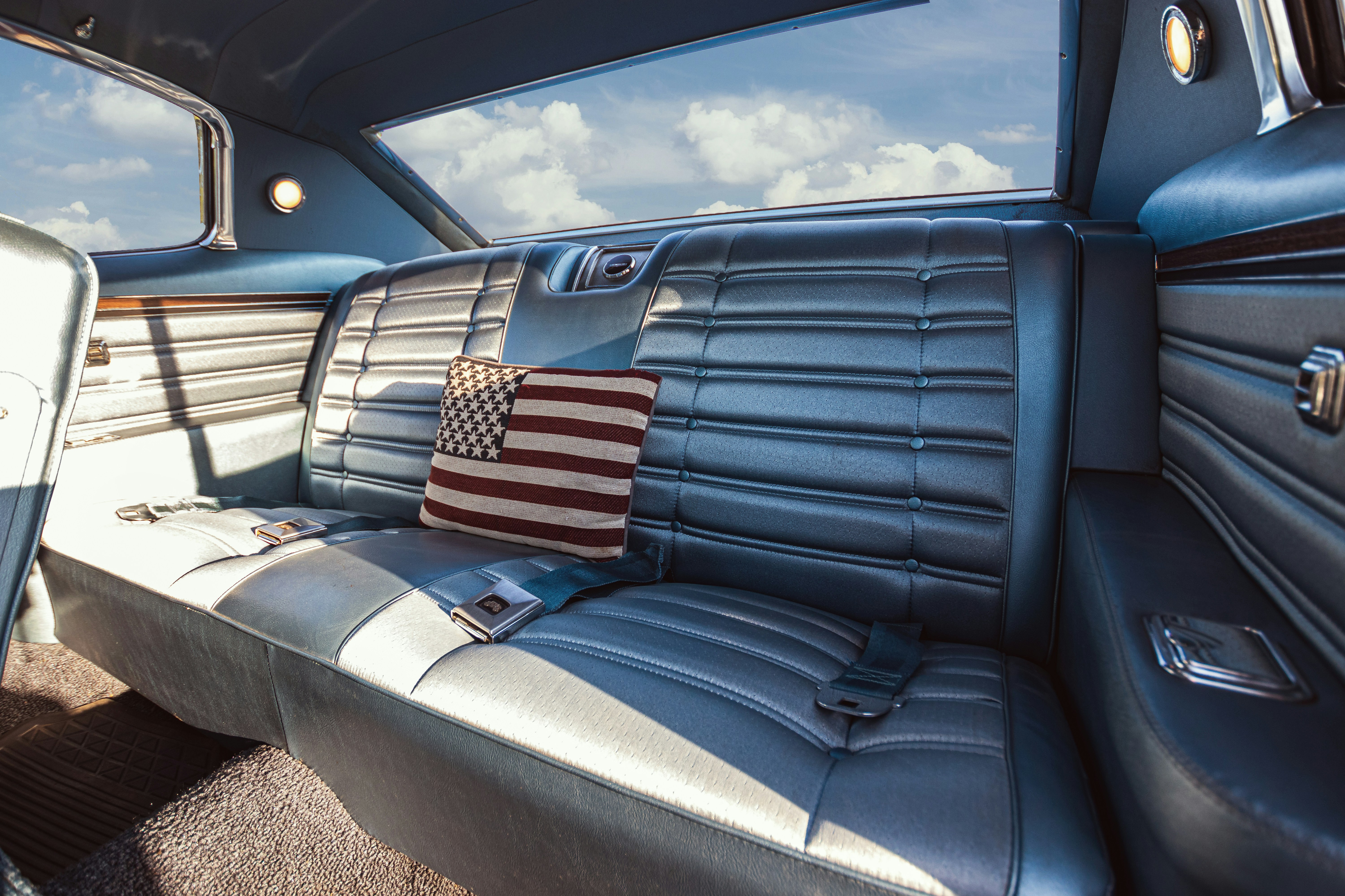 Patriotic Rest: Vintage Car Interior with Leather Bench and American Flag Pillow