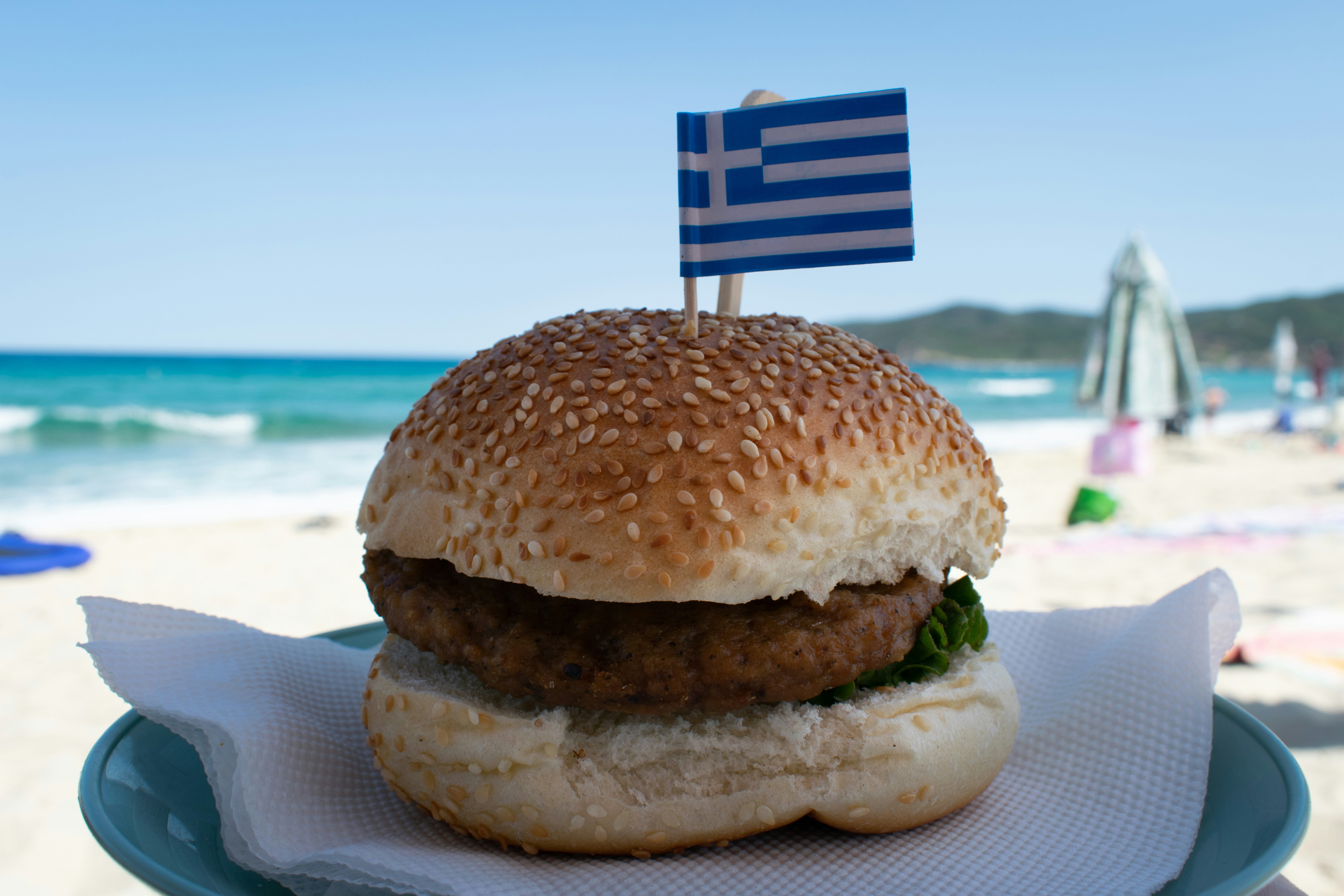 Sesame Crown by the Aegean Shore: Beachside Burger with a Flag