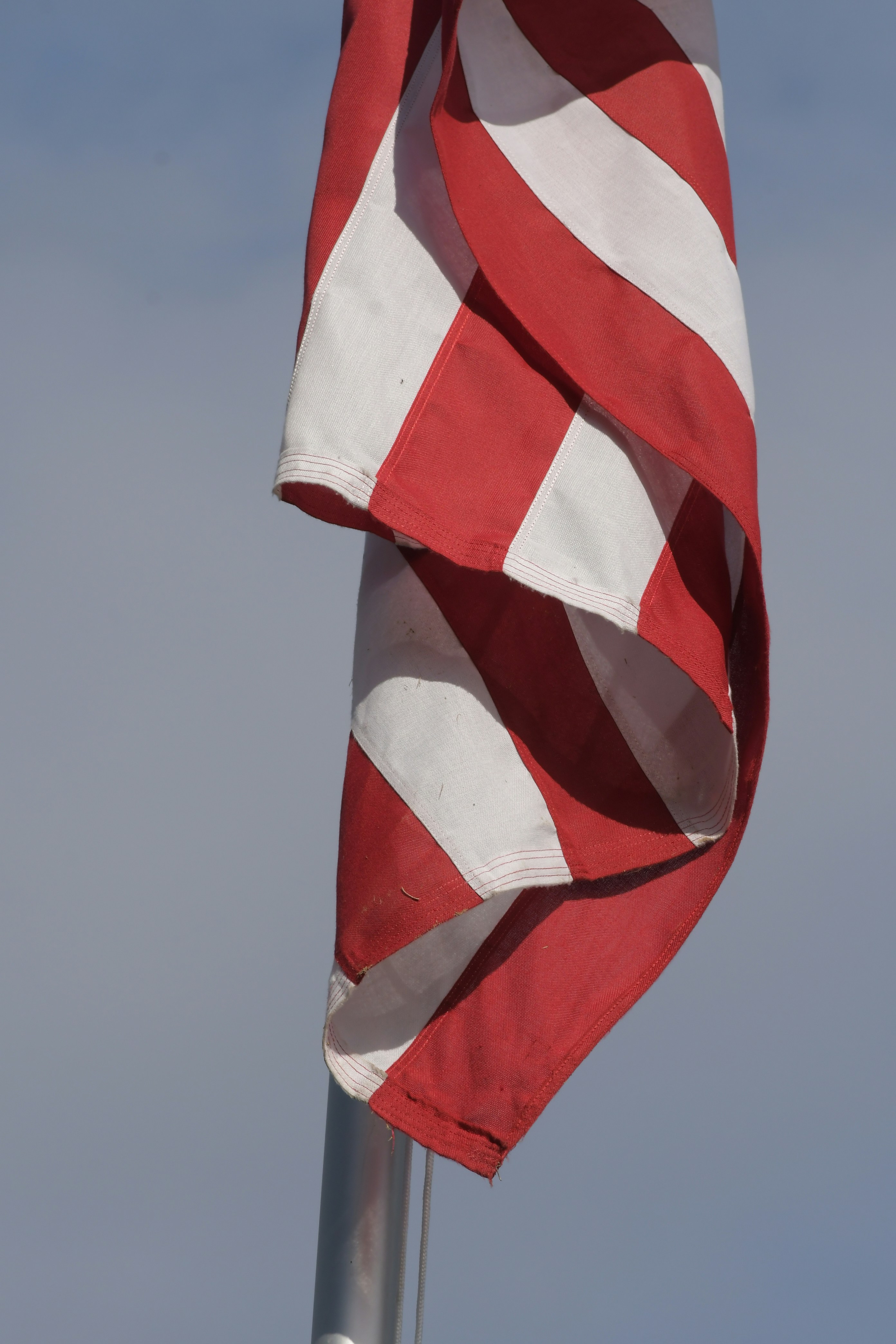 Draped Stripes: Red-and-White Flag Framed by a Clear Sky