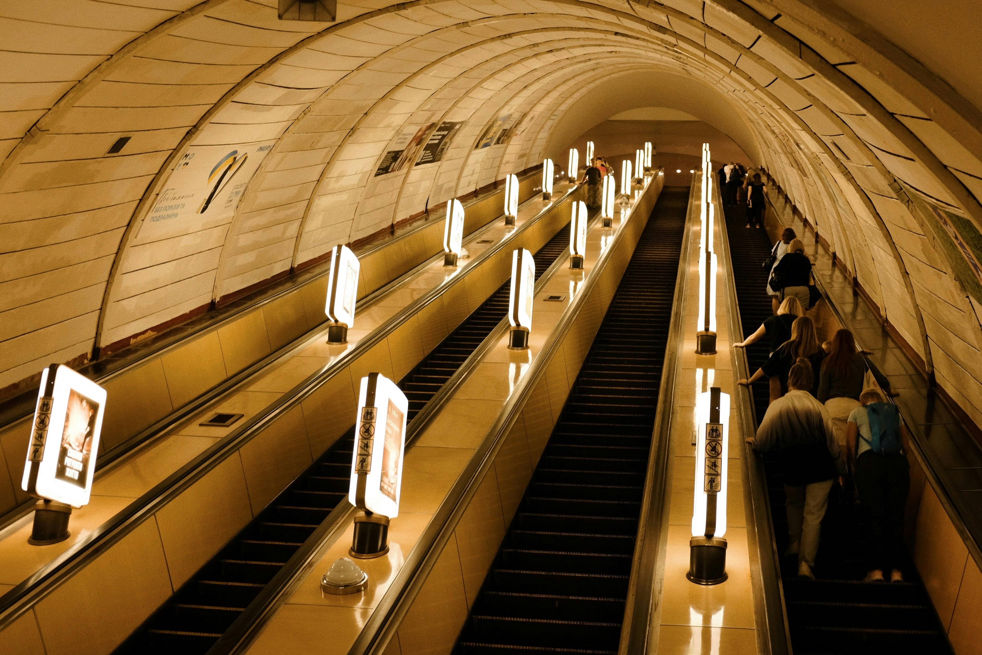 A group of people riding down an escalator photo – Free Street ...