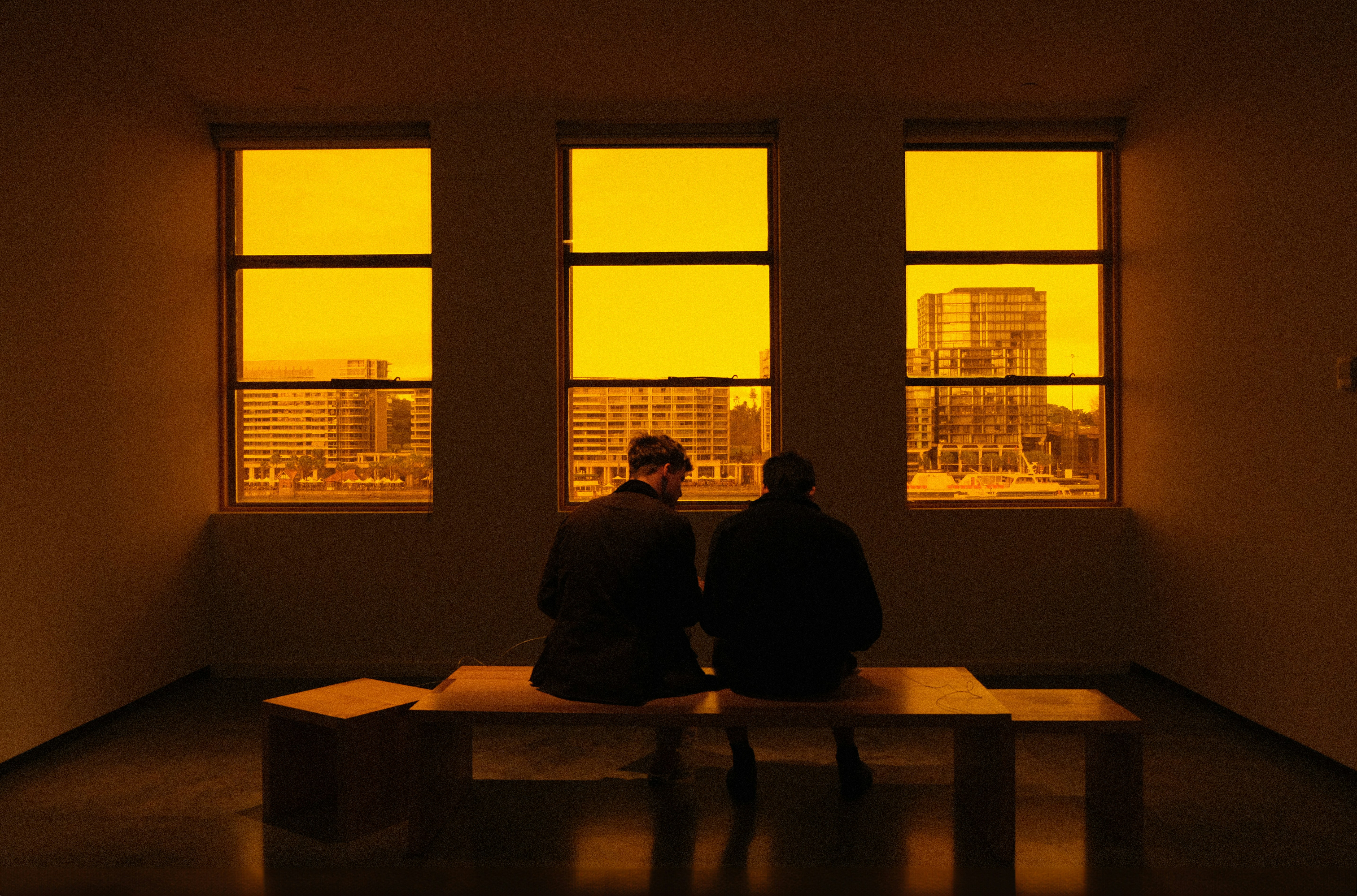 Two people sitting on a bench looking out a window photo – Free ...
