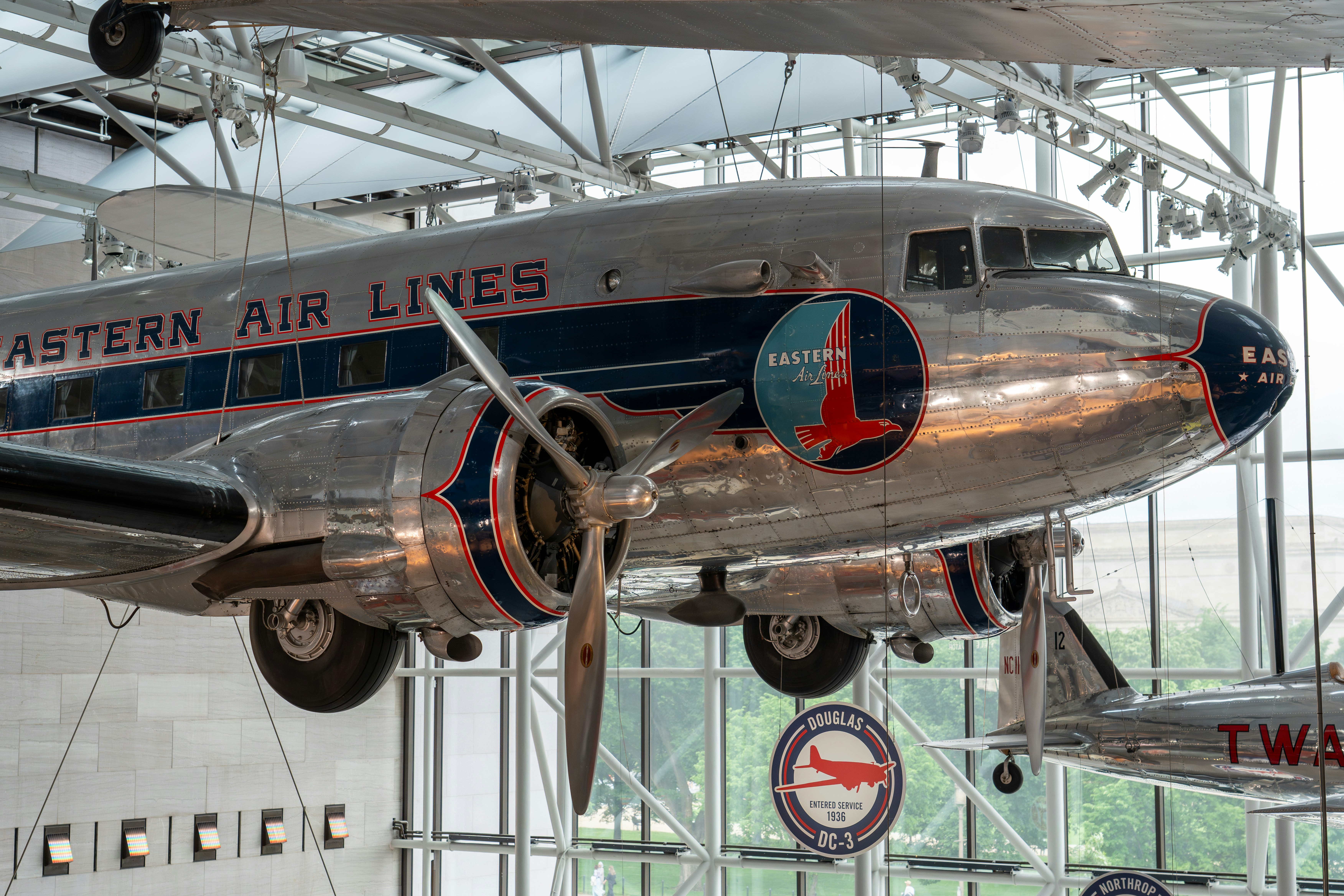 A silver airplane hanging from the ceiling of a building photo – Free ...