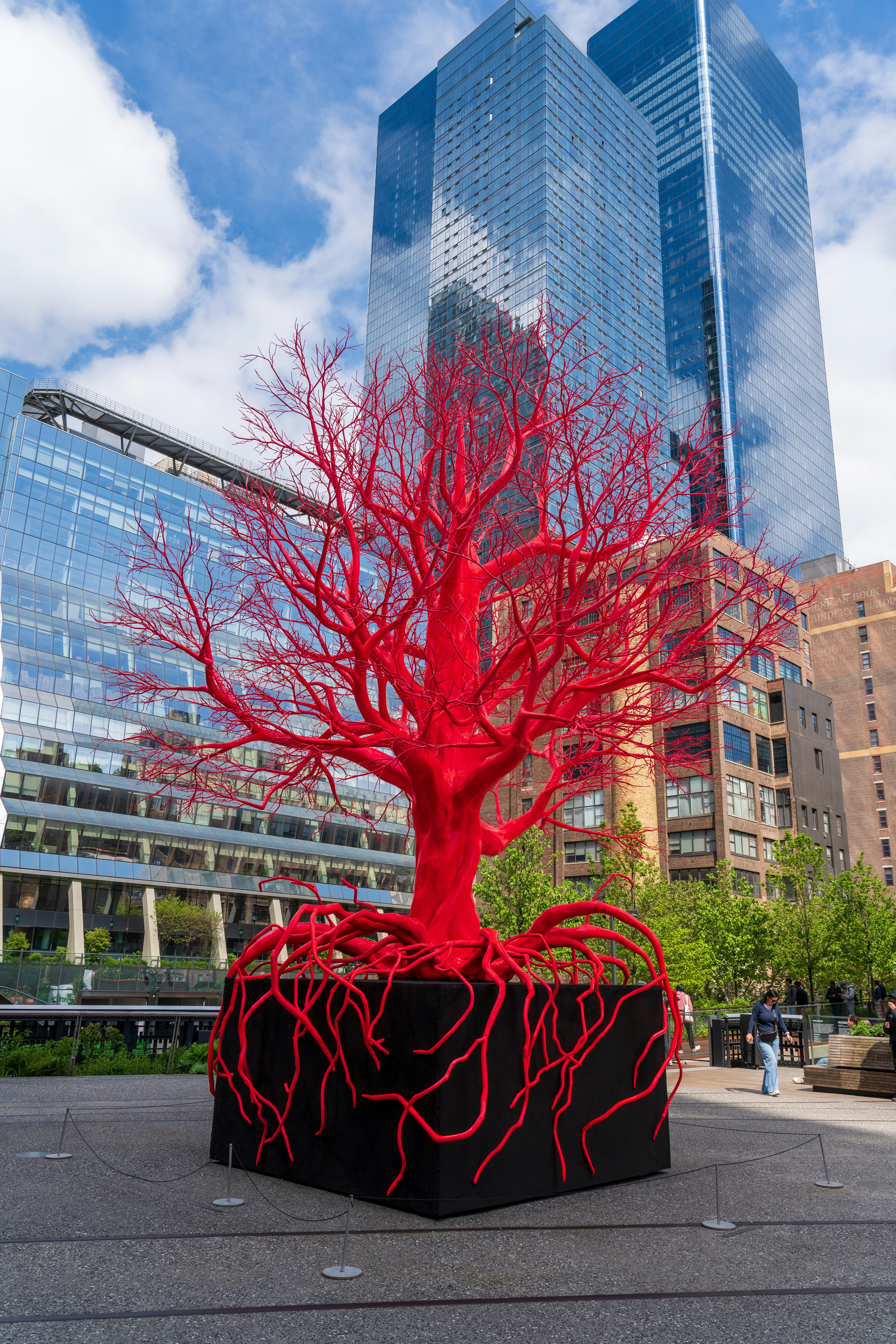 A sculpture of a red tree in front of a tall building photo – Free New ...